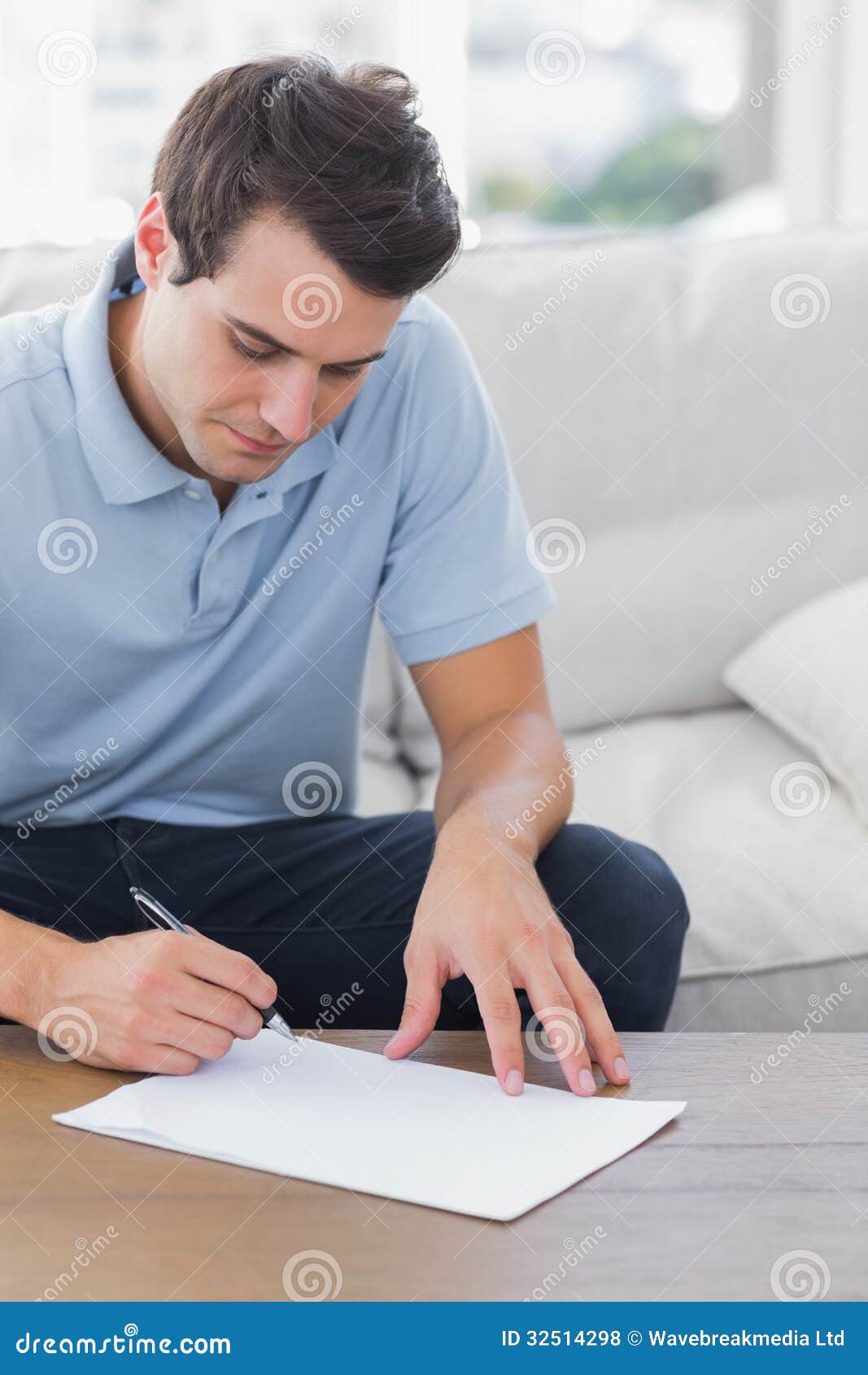 Man Writing on a Paper while he is Sat on a Couch Stock Photo - Image ...