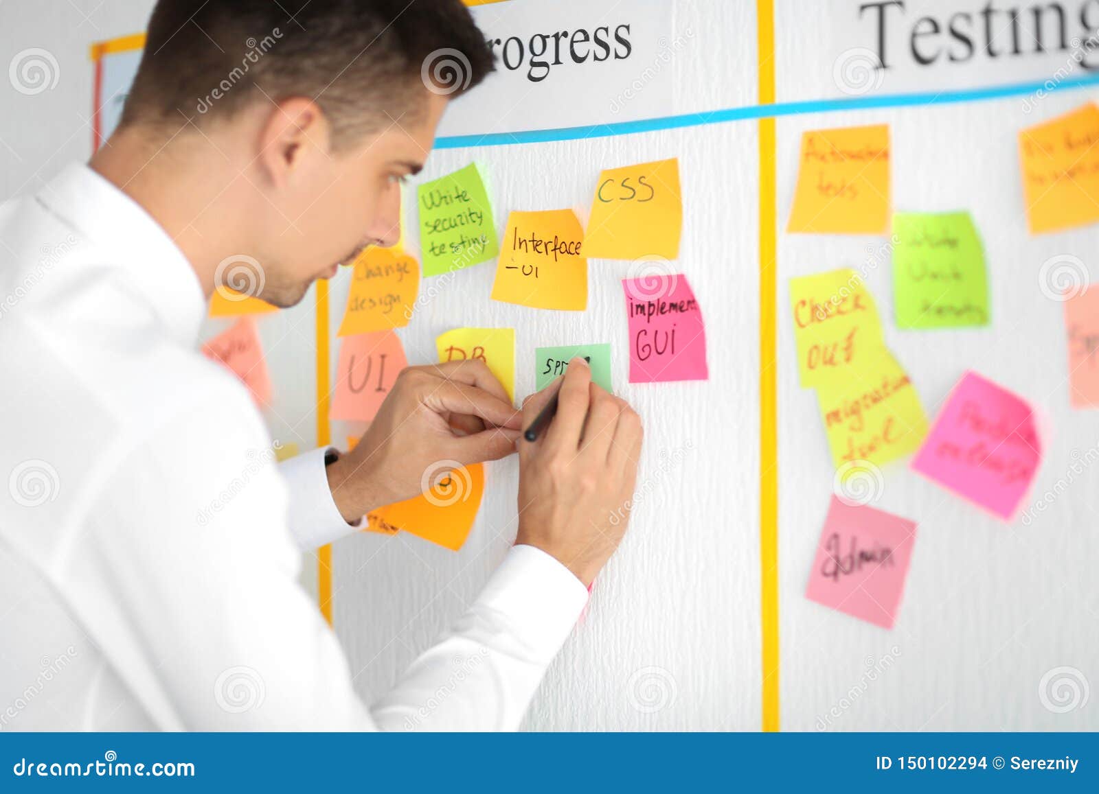 Man Writing on Sticky Note Attached To Scrum Task Board in Office Stock ...