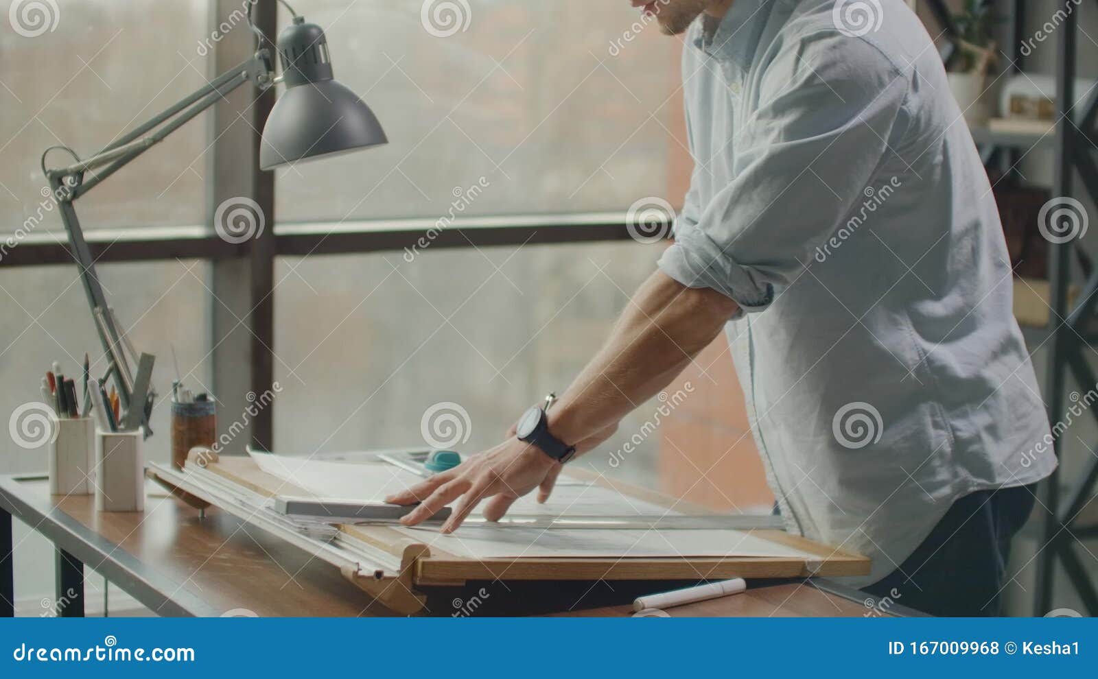 A Man is a Young Modern Architect Sitting at a Table Drawing a Plan of ...