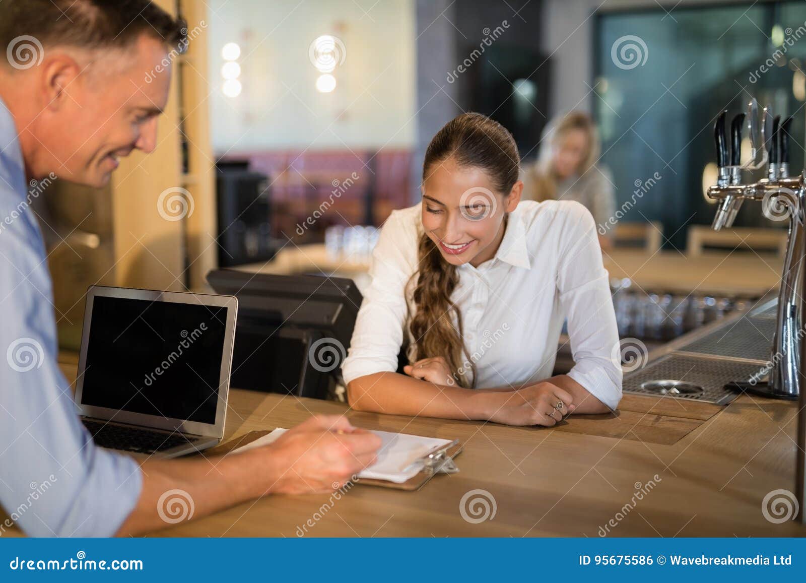 Manager and Bartender Discussing Over Clipboard in Bar Stock Photo ...