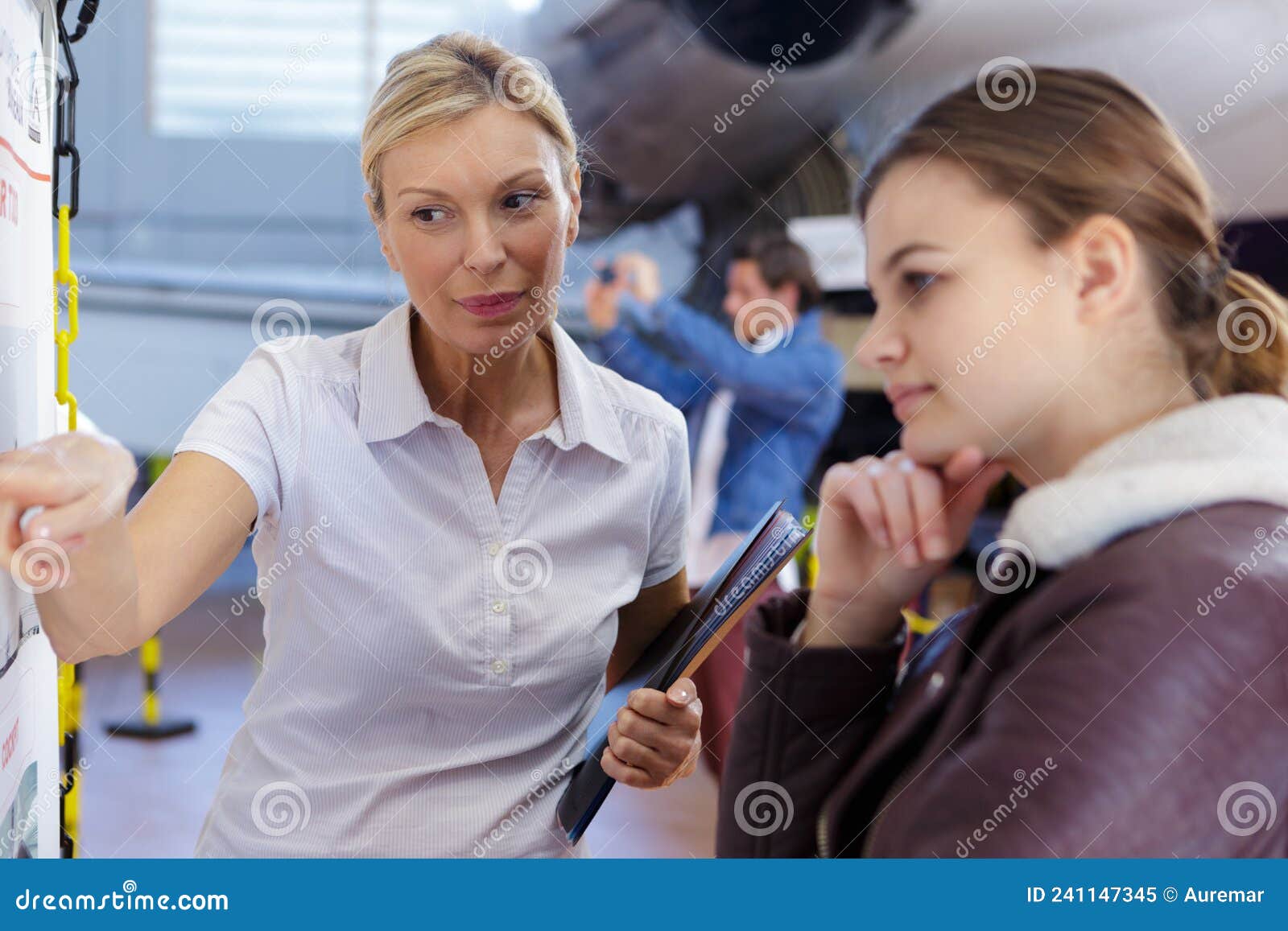Manager Discussing with Female Apprentice in Hangar Stock Image - Image ...