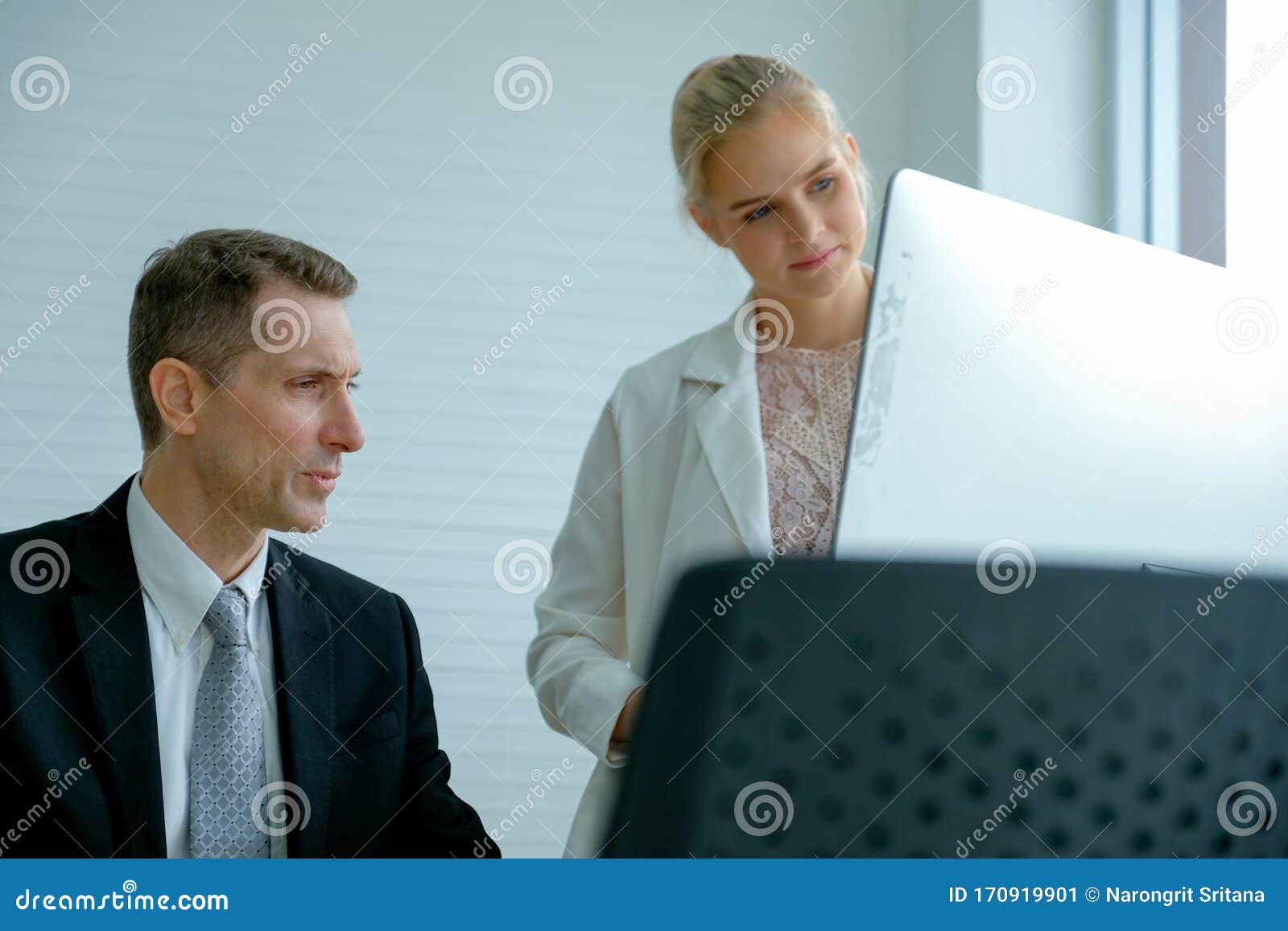 The Manager Look To Computer Screen and Young Secretary Stand Near Him ...