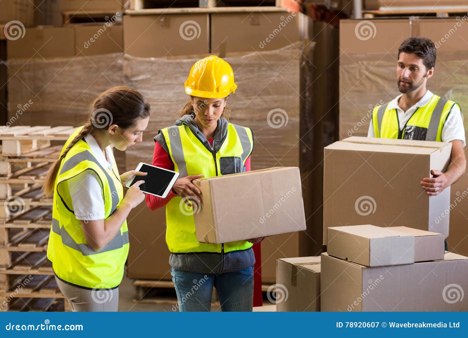 Manager Noting on Digital Tablet while Workers Carrying Cardboard Boxes ...