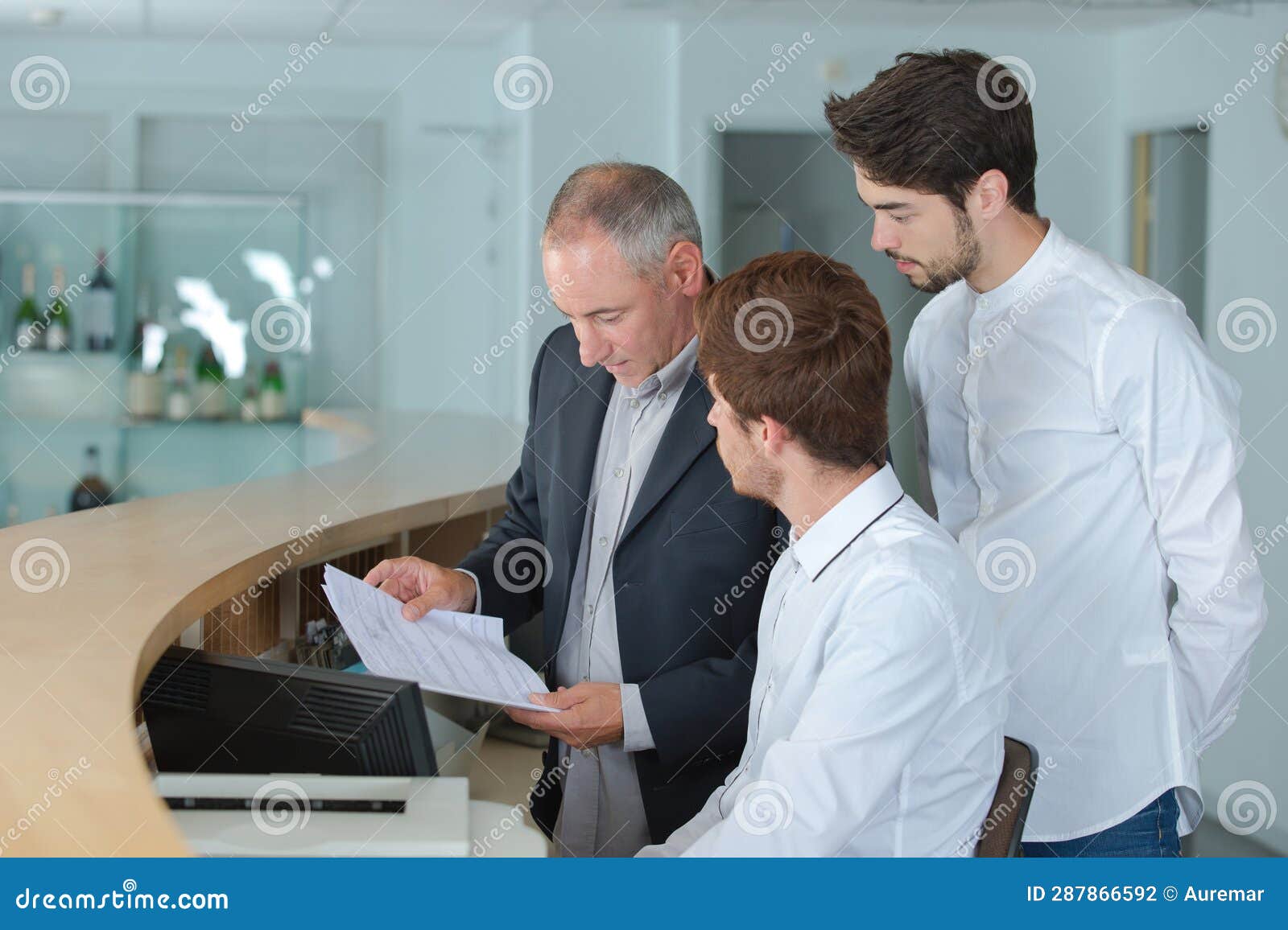Manager Showing Paperwork To Hotel Reception Staff Stock Photo - Image ...