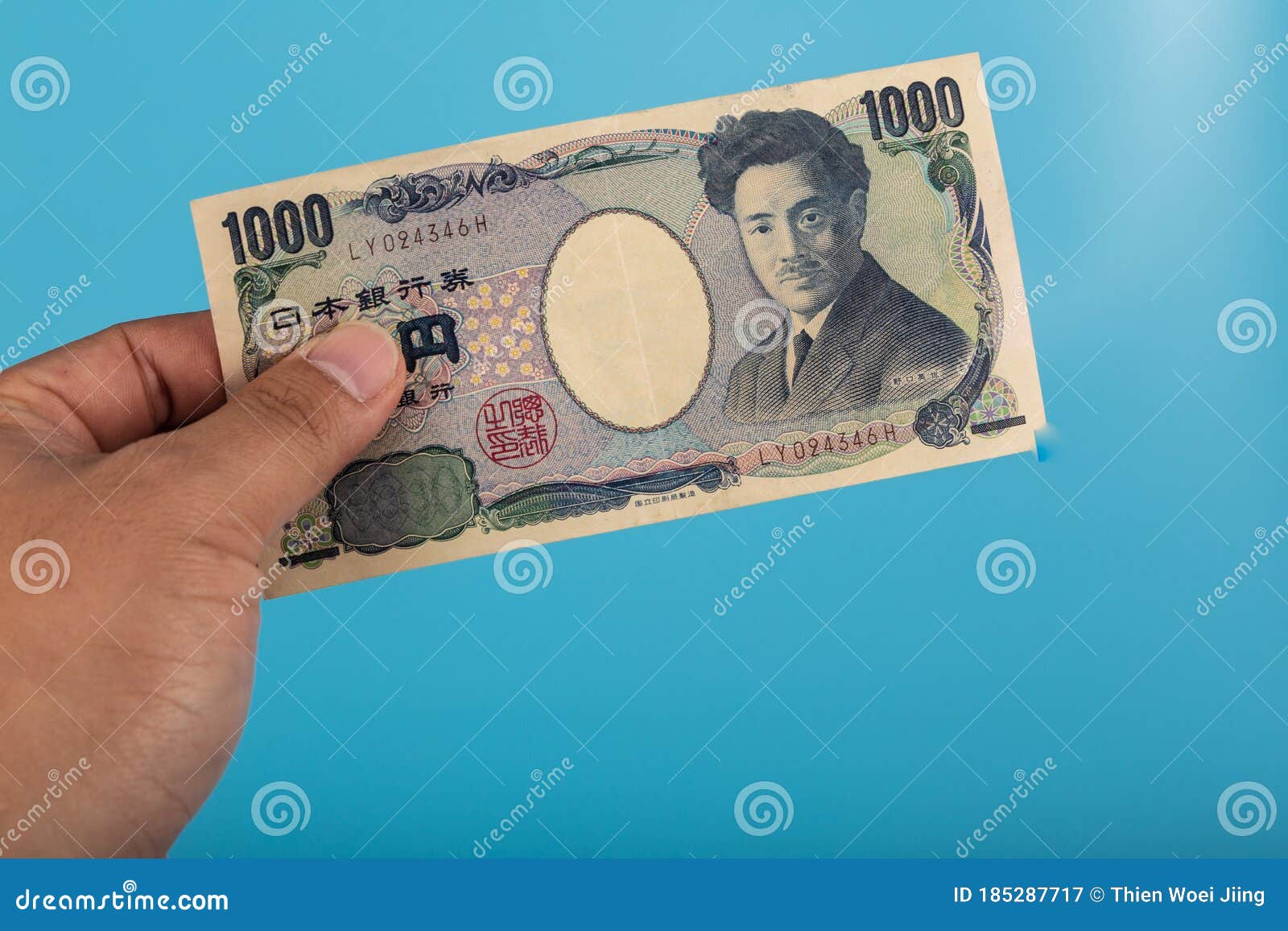 A Mans Hand is Holding One 1000 Japanese Yen Notes on Blue Background ...