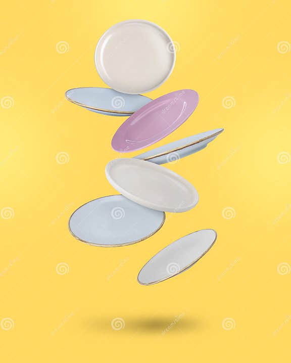 Many Different Plates Falling on Yellow Background Stock Photo - Image ...