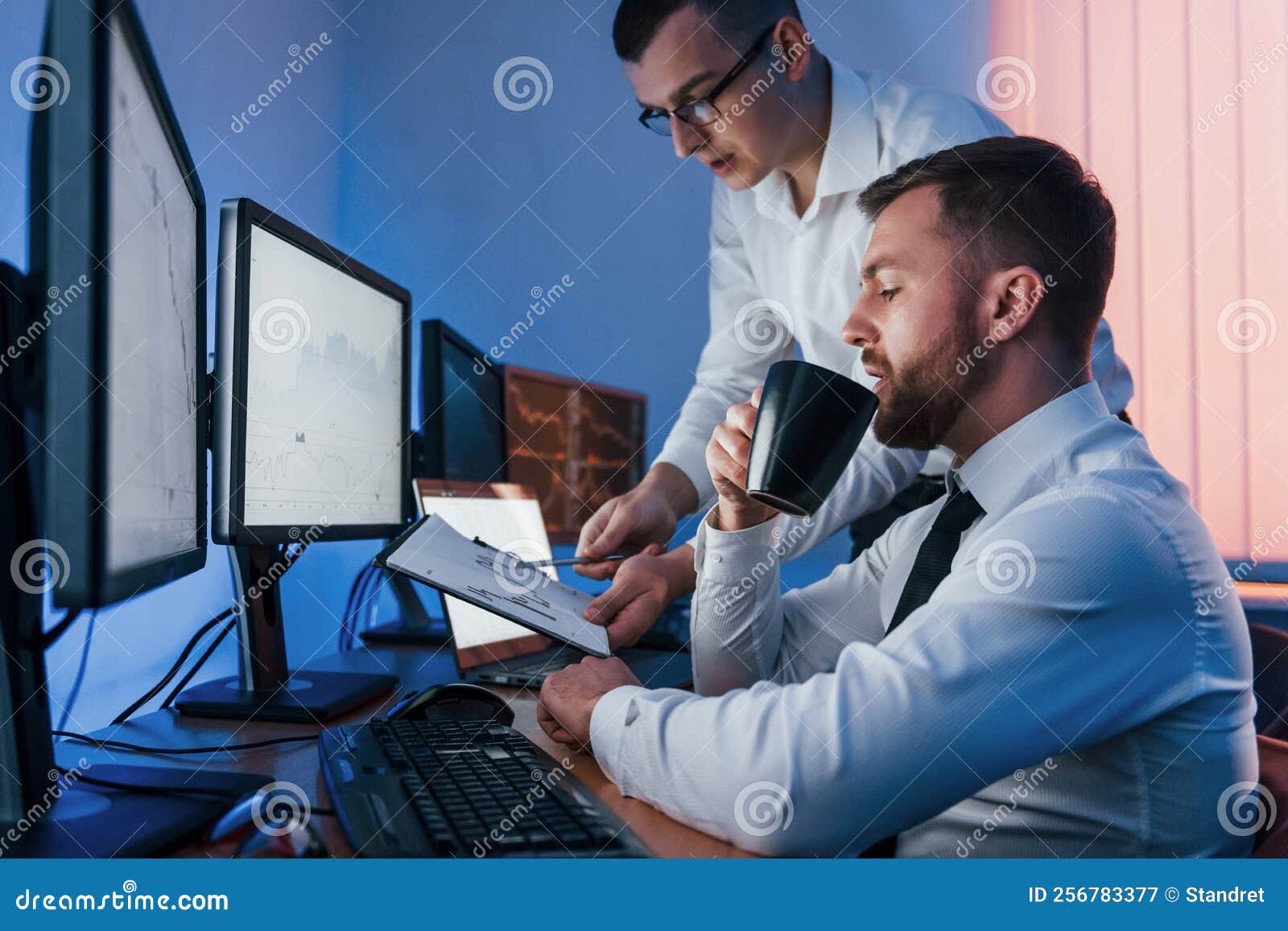 Many Displays on the Table. Two Stock Traders Working in the Office ...