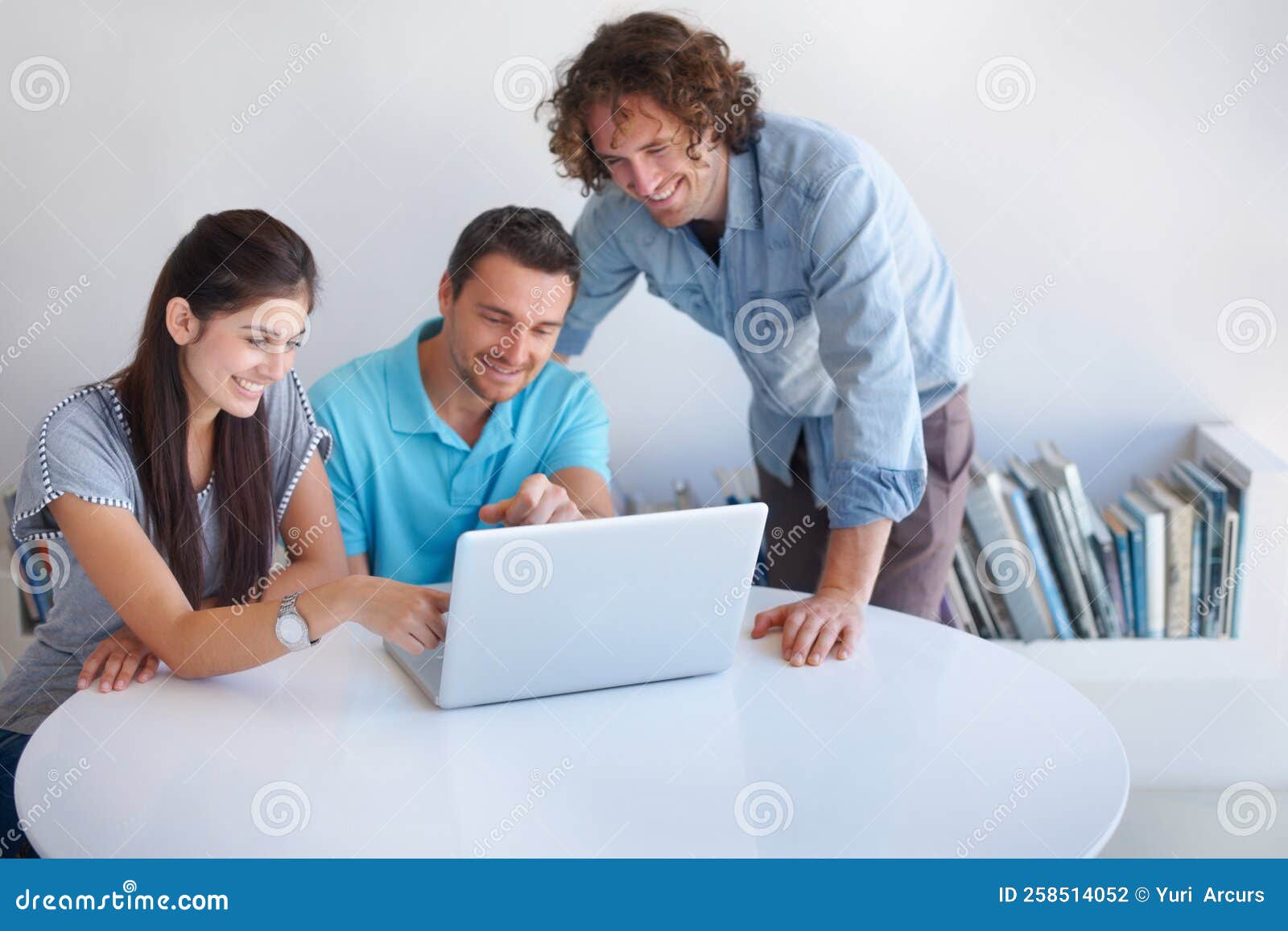 Many Hands Make Light Work. Three Coworkers Gathered Around a Laptop in ...