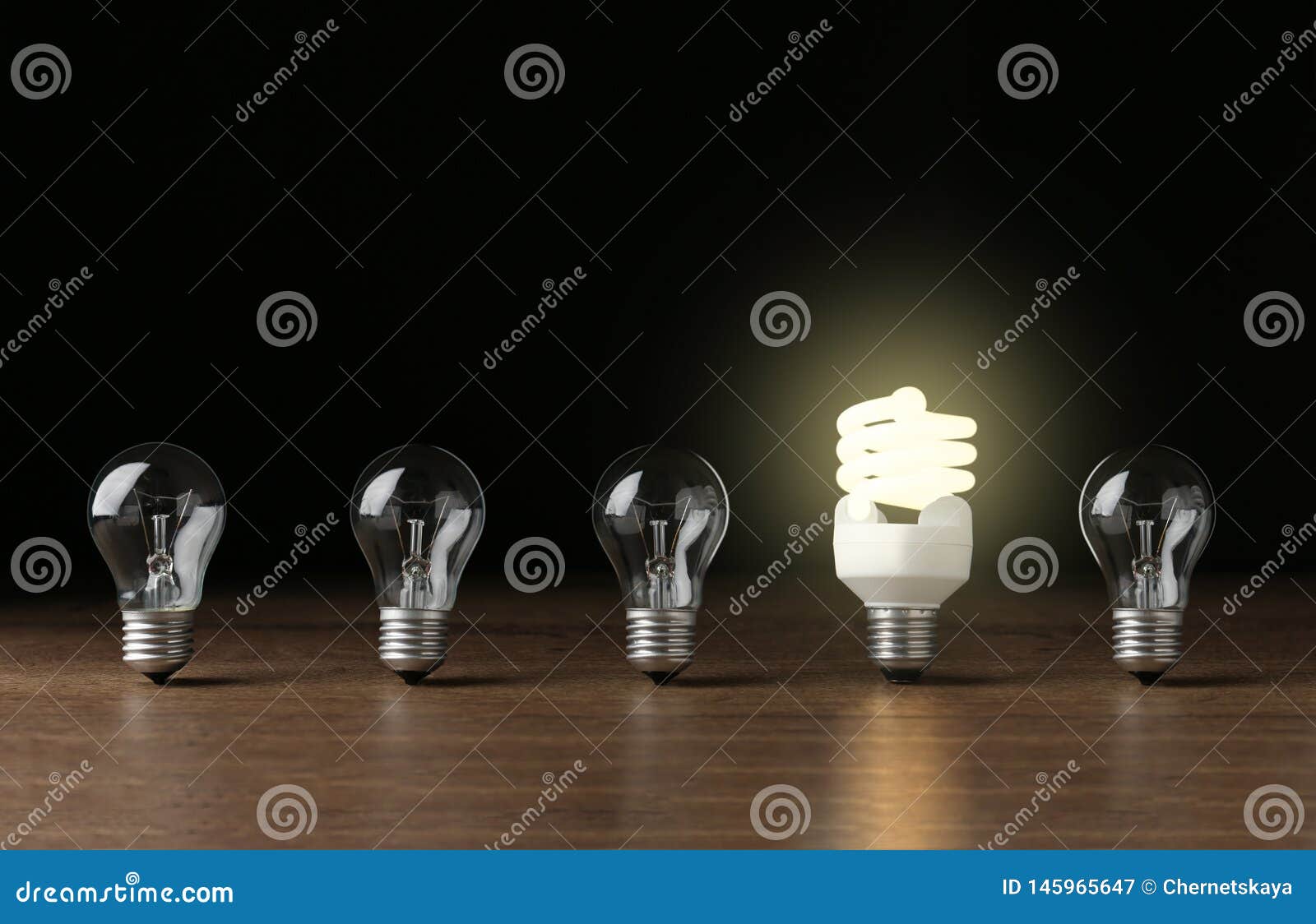 Many Lamp Bulbs on Table Against Dark Background. Symbol of Idea and ...