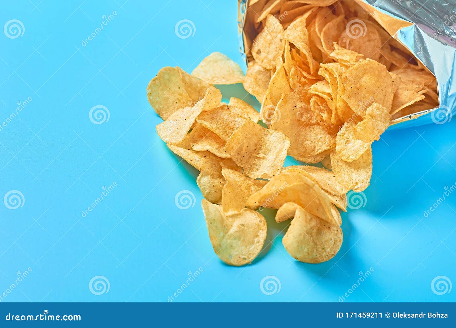 Many Potato Chips Poured Out Of Shiny Packaging On Blue Background ...