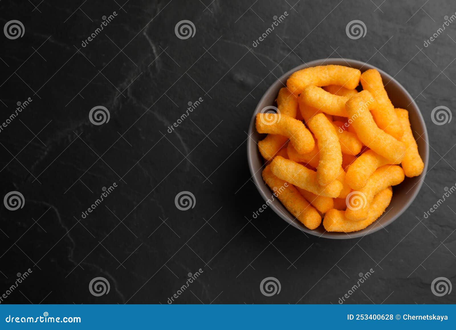 Many Tasty Cheesy Corn Puffs in Bowl on Black Table, Top View. Space ...
