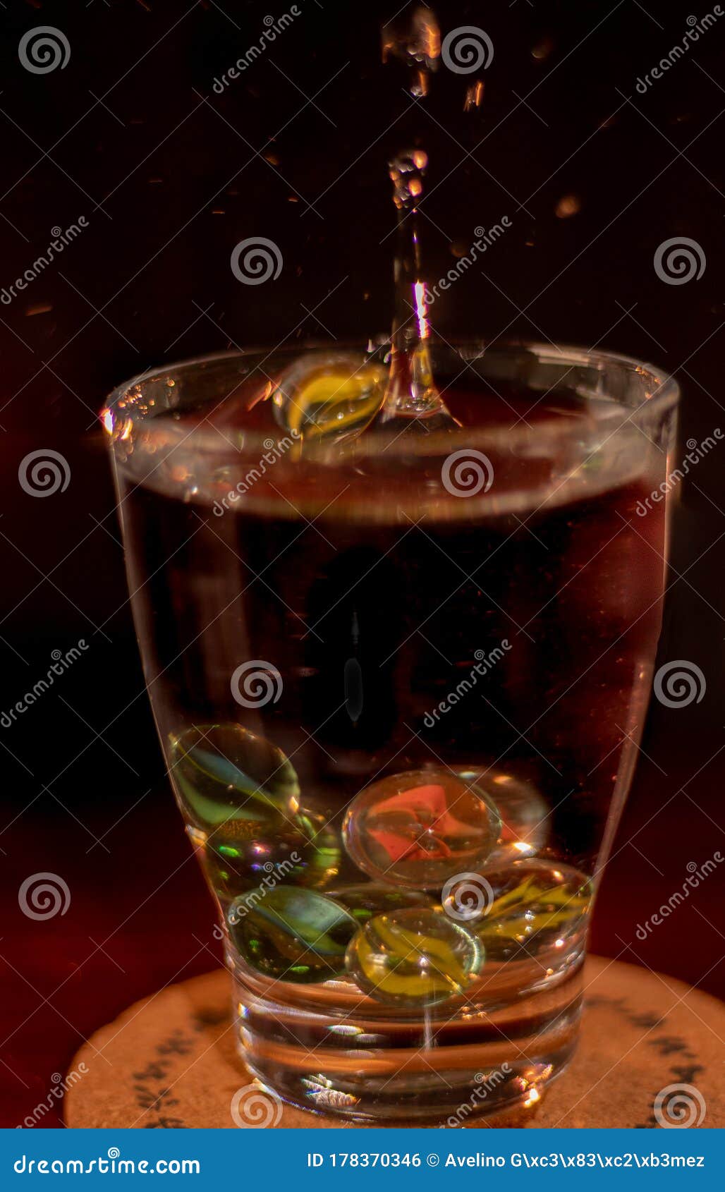 Marbles Falling into a Glass of Water Stock Photo - Image of dripped ...