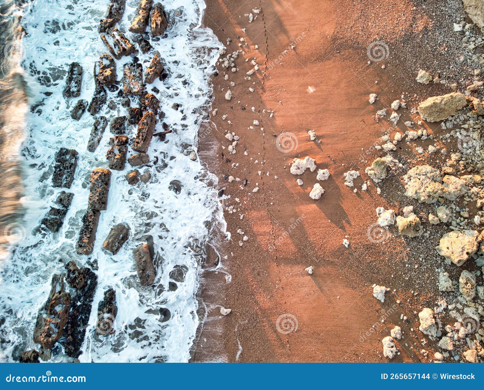 Marea Espumosa Salpicando Una Orilla De Arena Con Rocas Foto de archivo ...