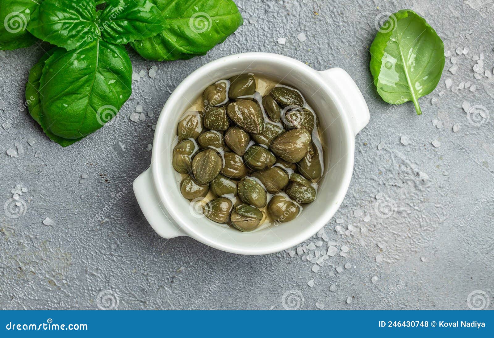 Marinated Capers with Fresh Basil Leaves in a Small Bowl, on Gray ...