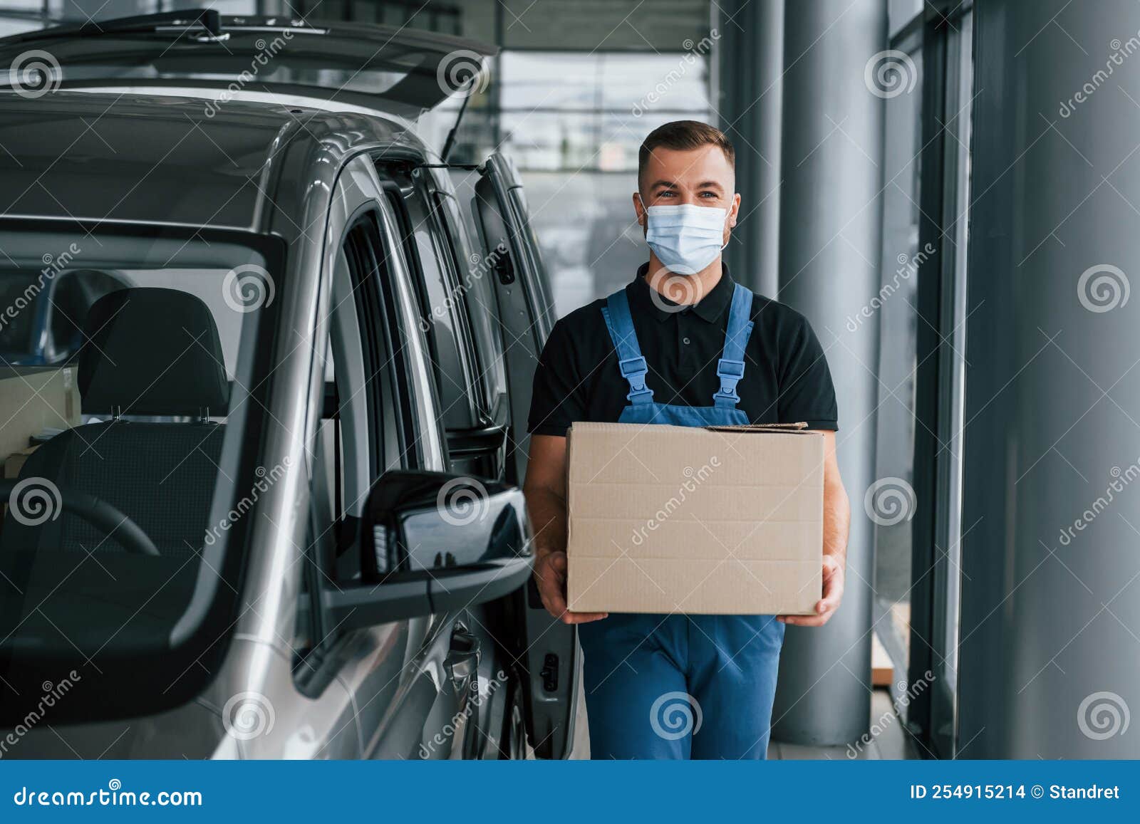 In Mask. Delivery Man in Uniform is Indoors with Car and with Order ...
