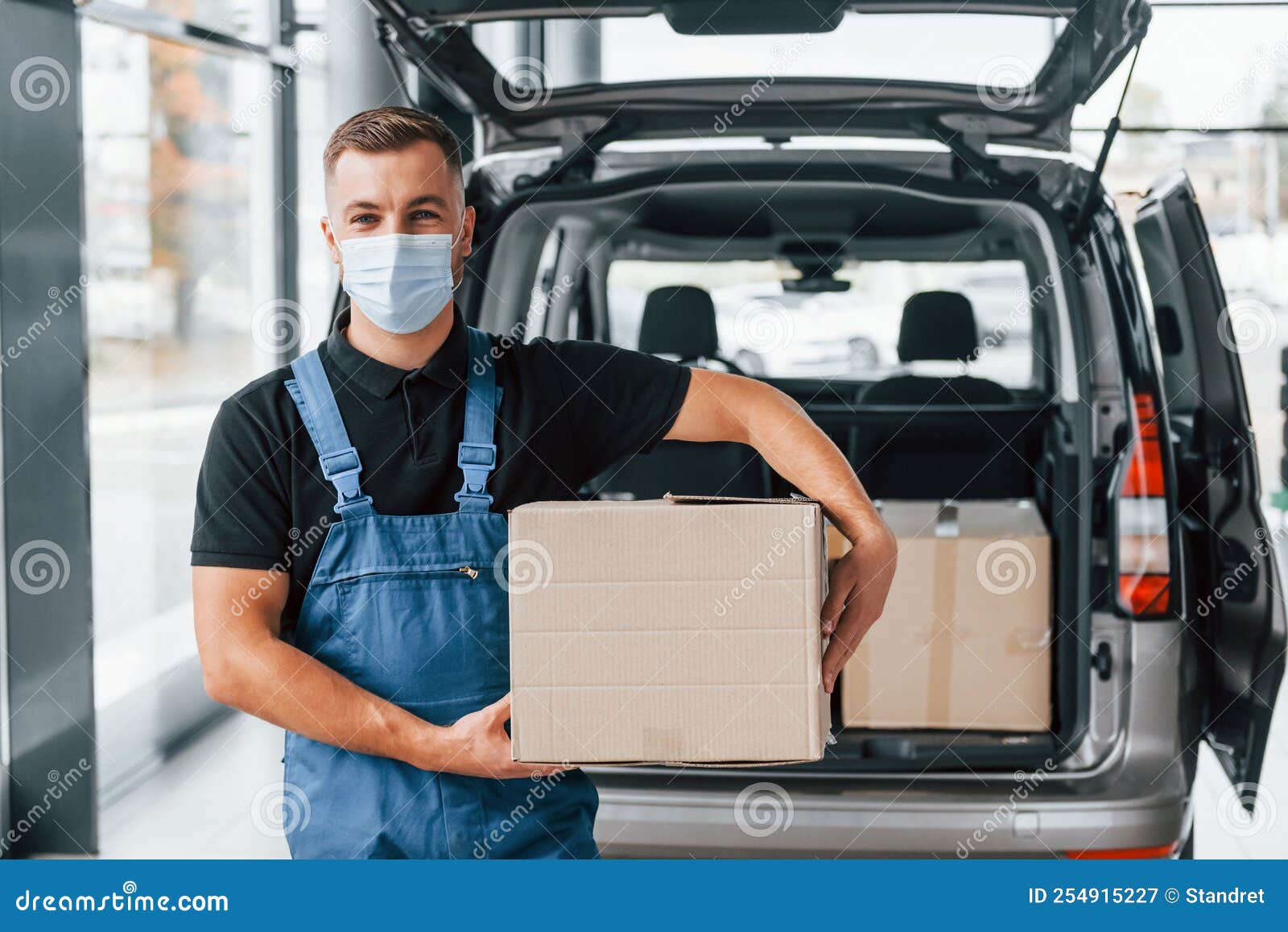 In Mask. Delivery Man in Uniform is Indoors with Car and with Order ...