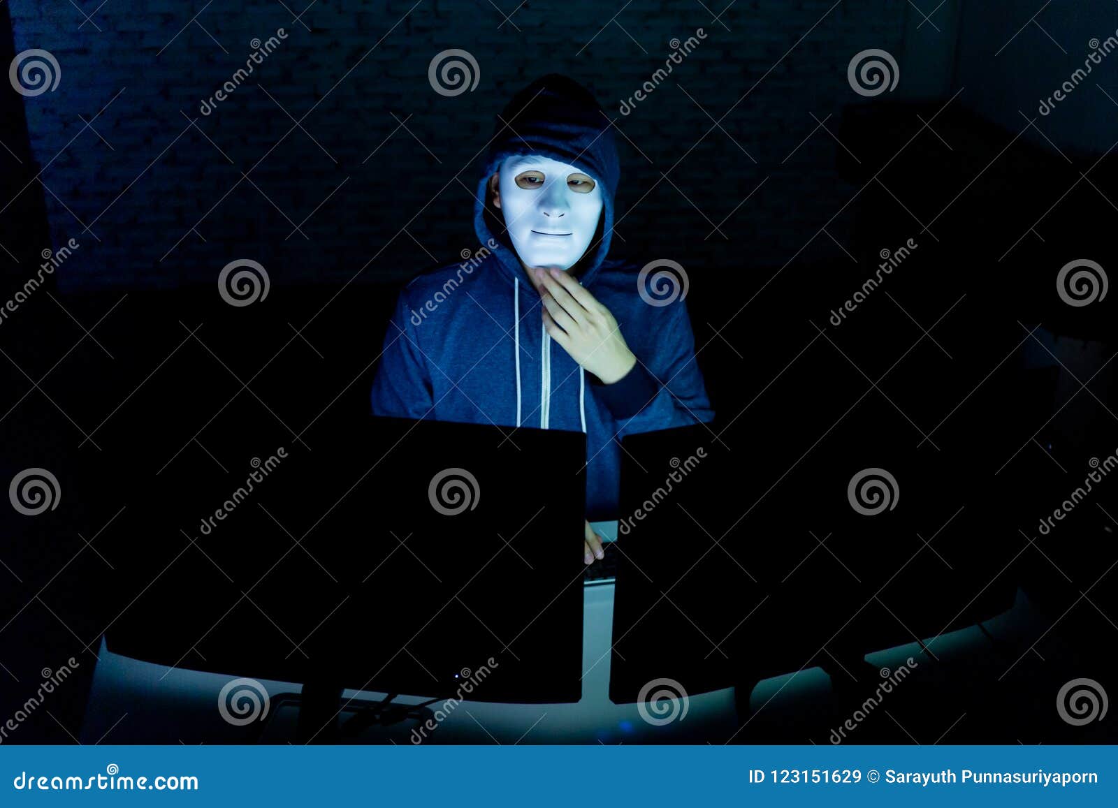 Masked Hacker Under Hood Using Computer To Hack Into System And Trying To Commit Computer Crime