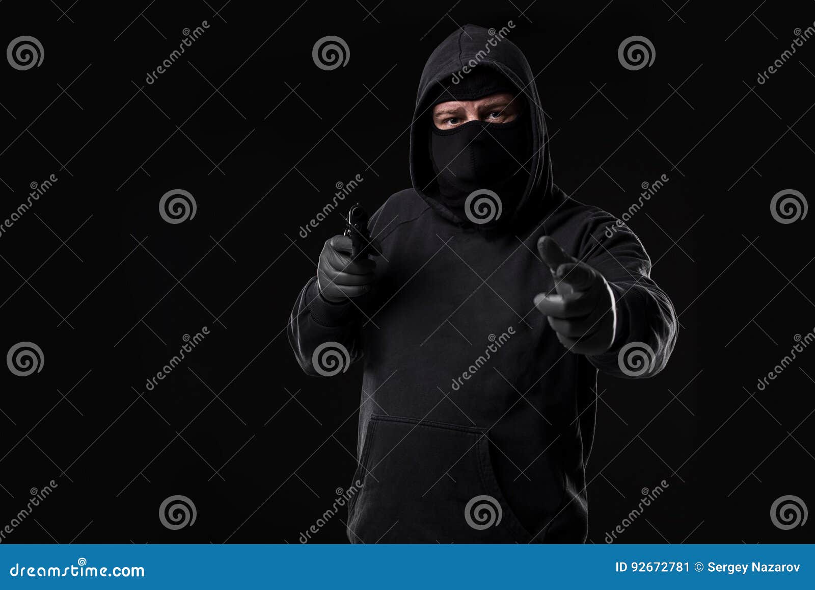 Masked Robber with Gun Aiming into the Camera Against a Black ...