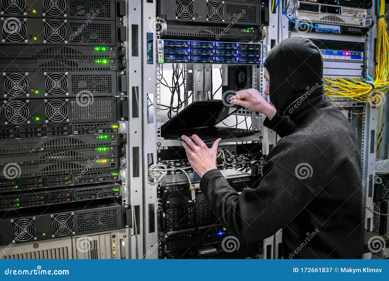 A Masked Thug Closes a Laptop in a Server Room. Hacker Breaks into a ...