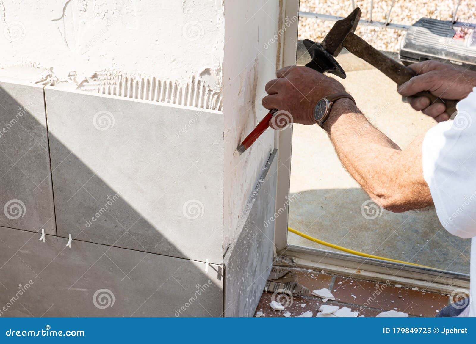 The Mason Prepares the Wall with a Chisel before Laying a Ceramic Tile ...