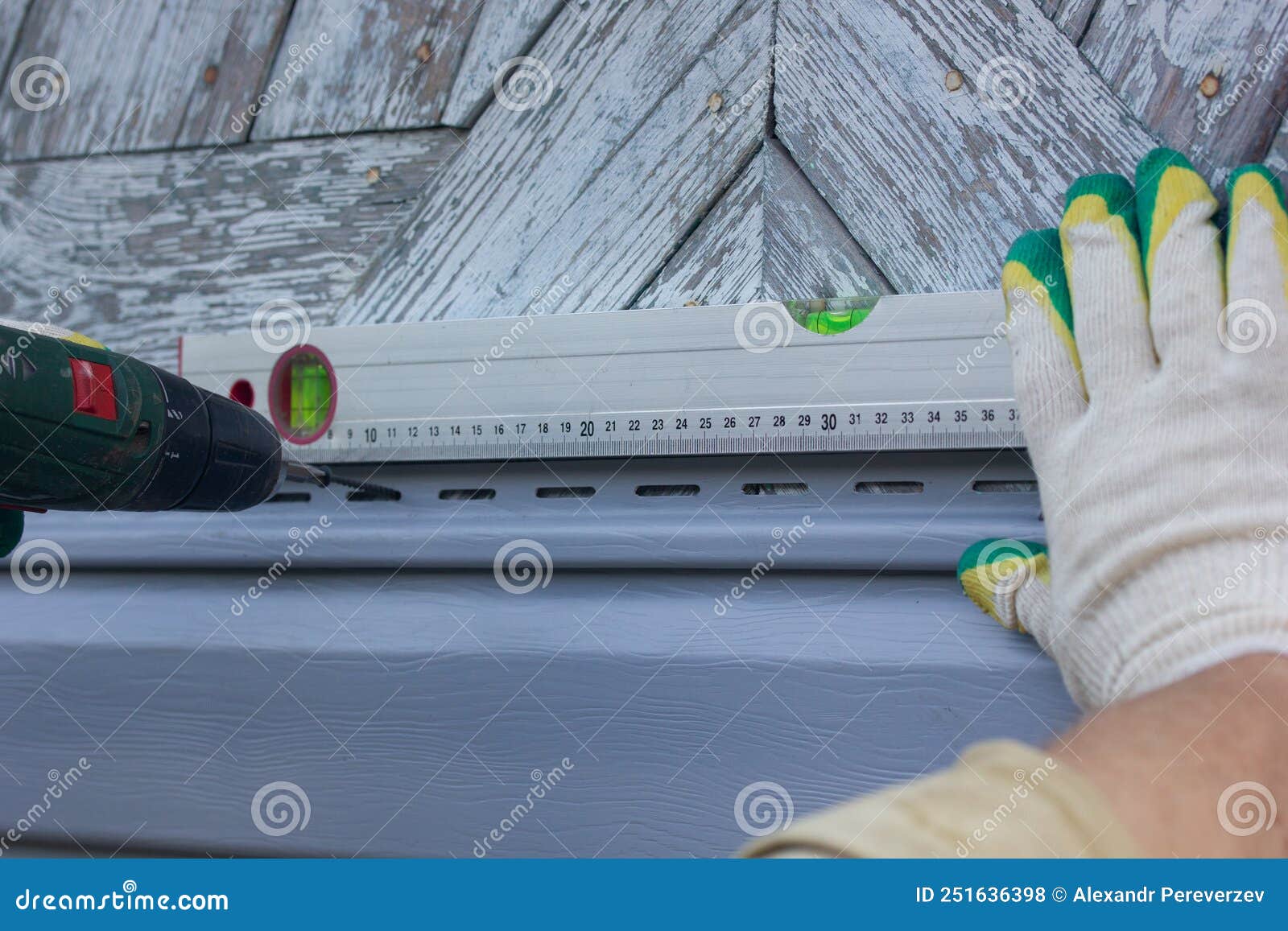 The Master Screws the Siding To the Wooden Wall with a Screwdriver and ...