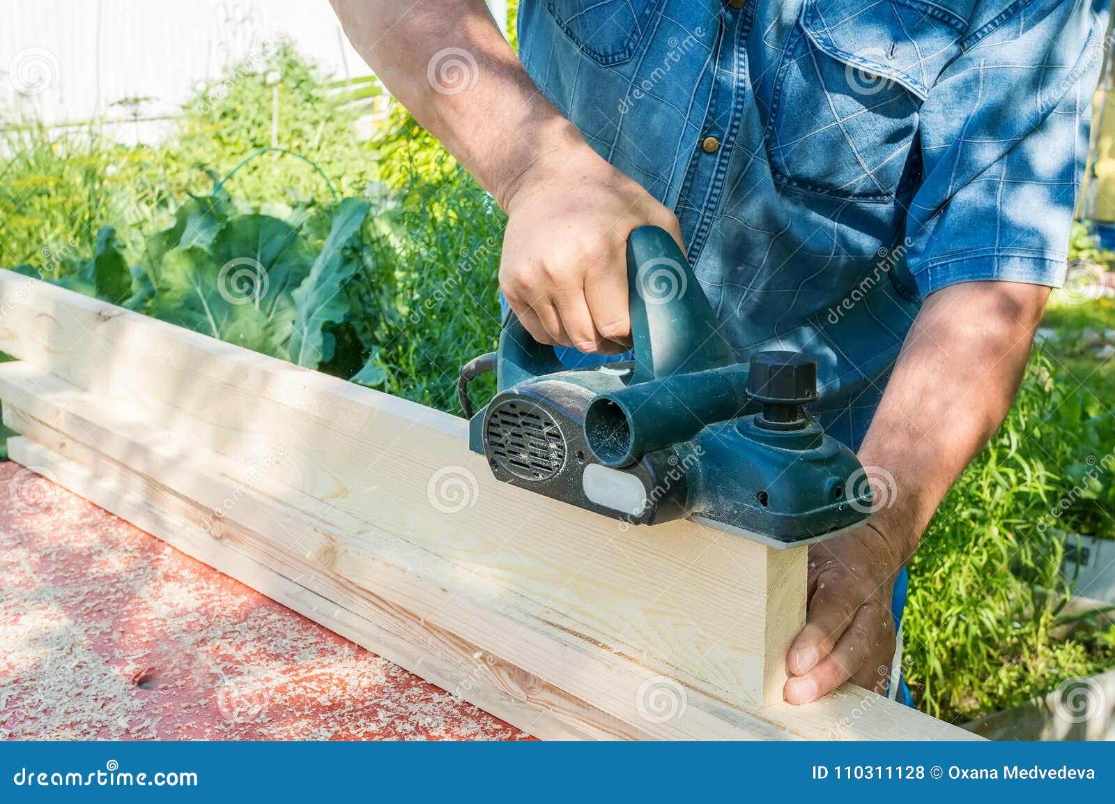 The Master Sharpens the Wooden Panel with an Electric Sander on a Sunny ...
