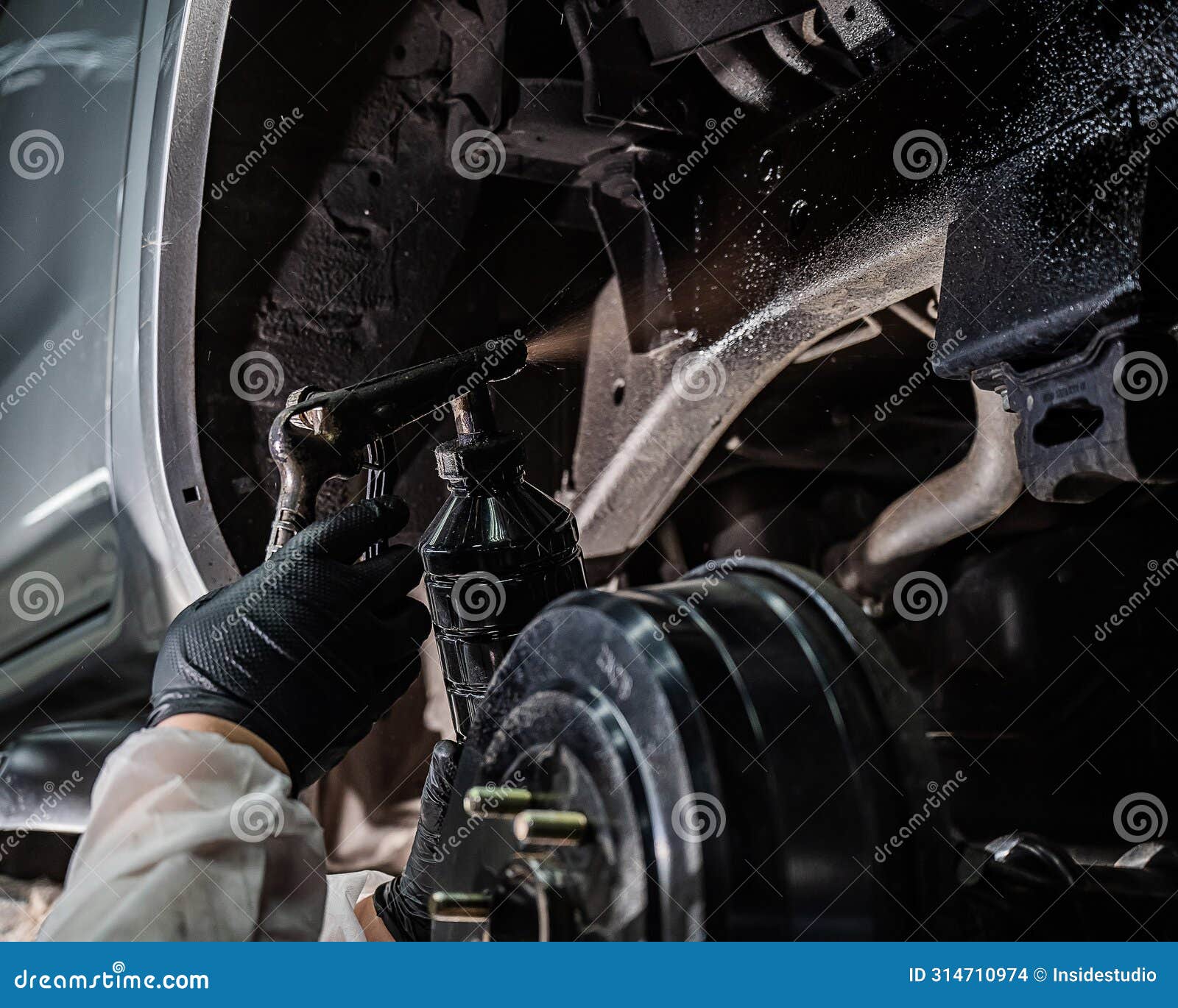The Master Sprays an Anti-corrosion Compound on the Bottom of the Car ...