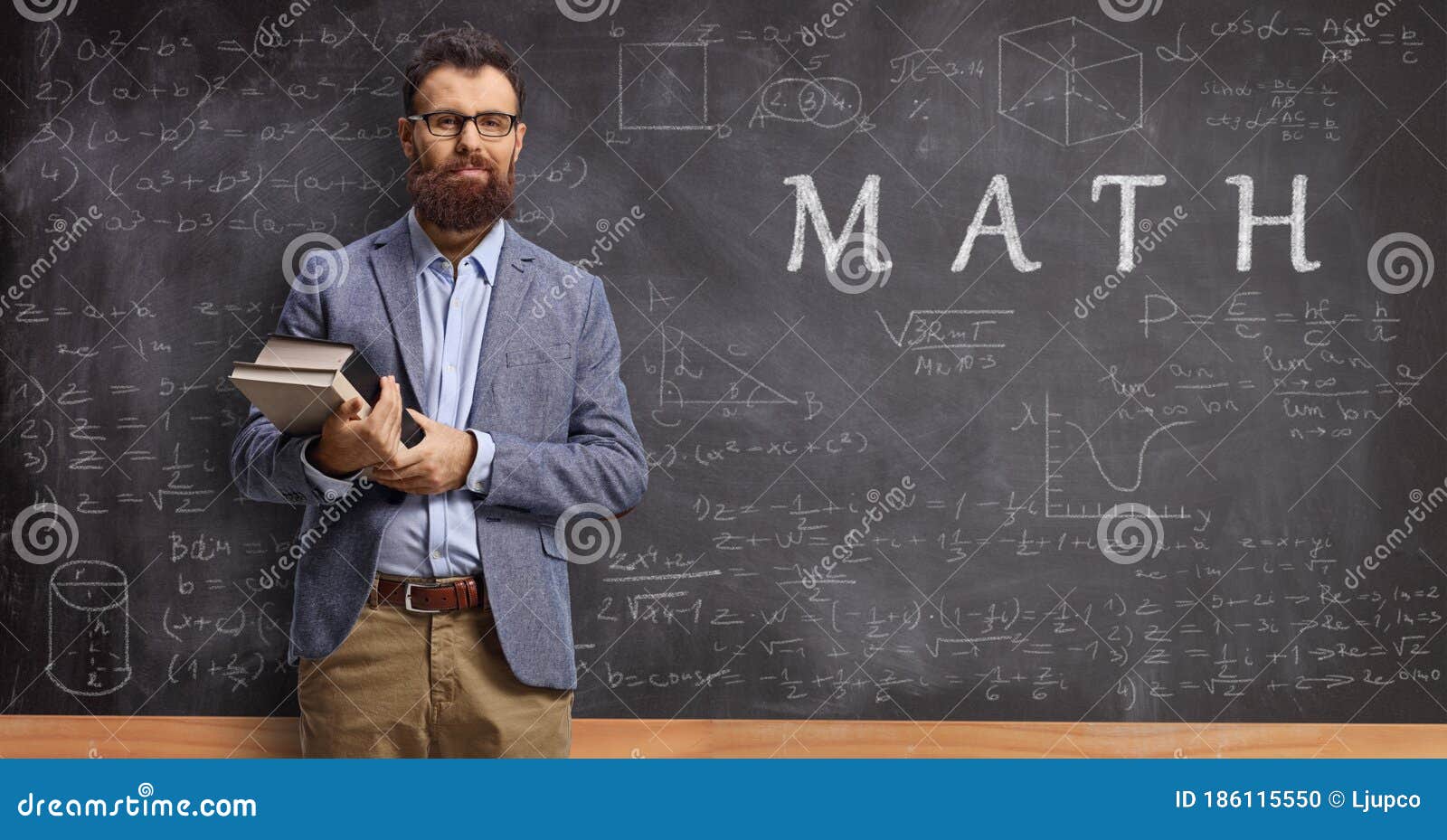Math Male Teacher Holding Books and Posing in Front of a Blackboard ...