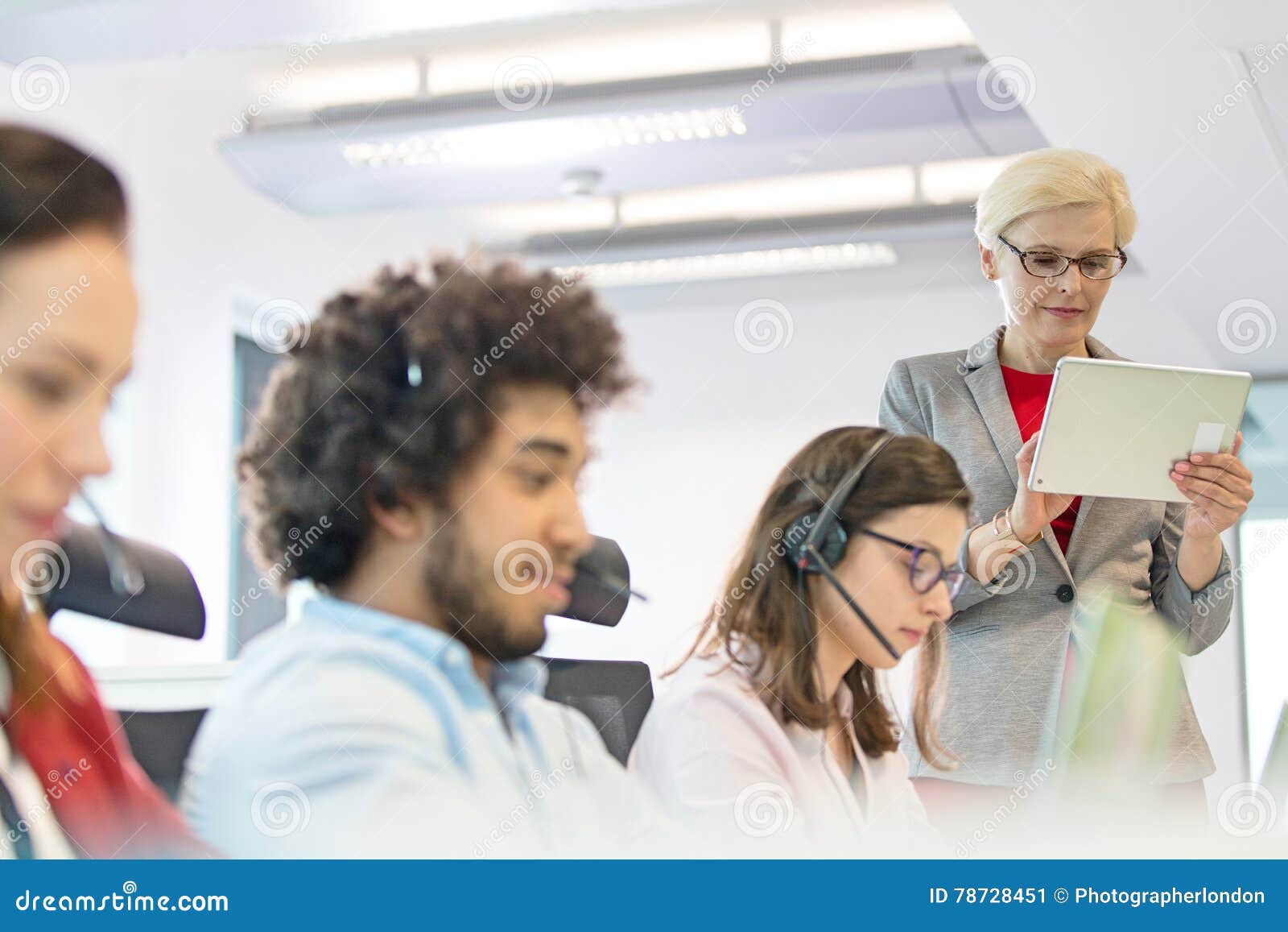 Mature Businesswoman Using Digital Tablet while Operators Working in ...