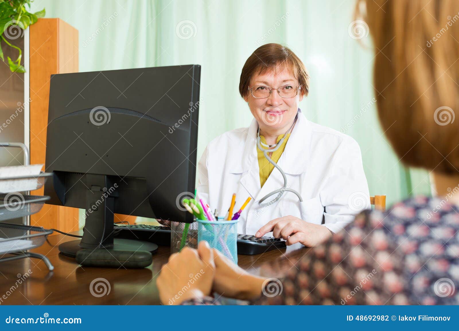 Mature Doctor Behind Computer with Patient Stock Photo - Image of ...