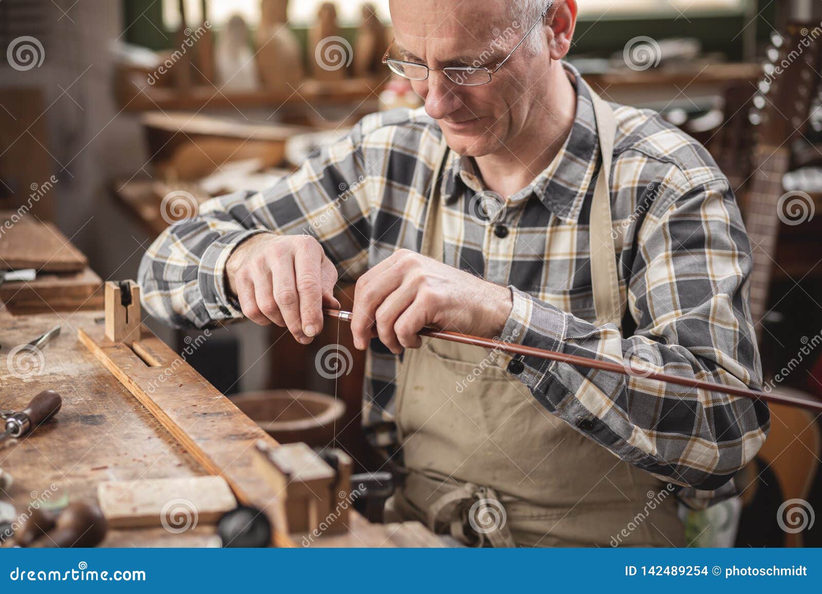 Mature Instrument Maker Inside A Rustic Workshop Is Winding A Wire ...