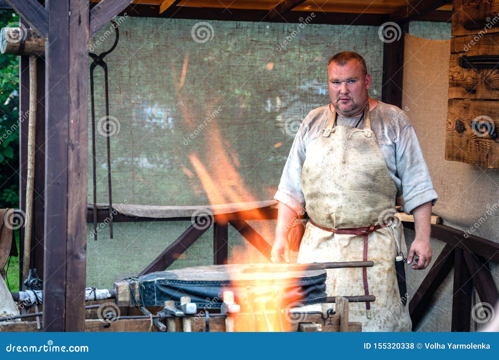 Mature Large Male Blacksmith in an Open Air Workshop Inflates Bellows ...