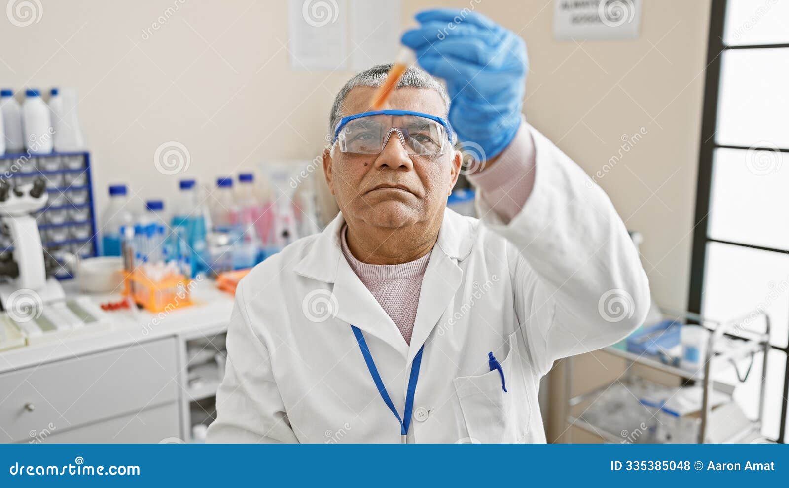 Mature Man in Lab Coat Holding Test Tube Inside a Laboratory Analyzing ...