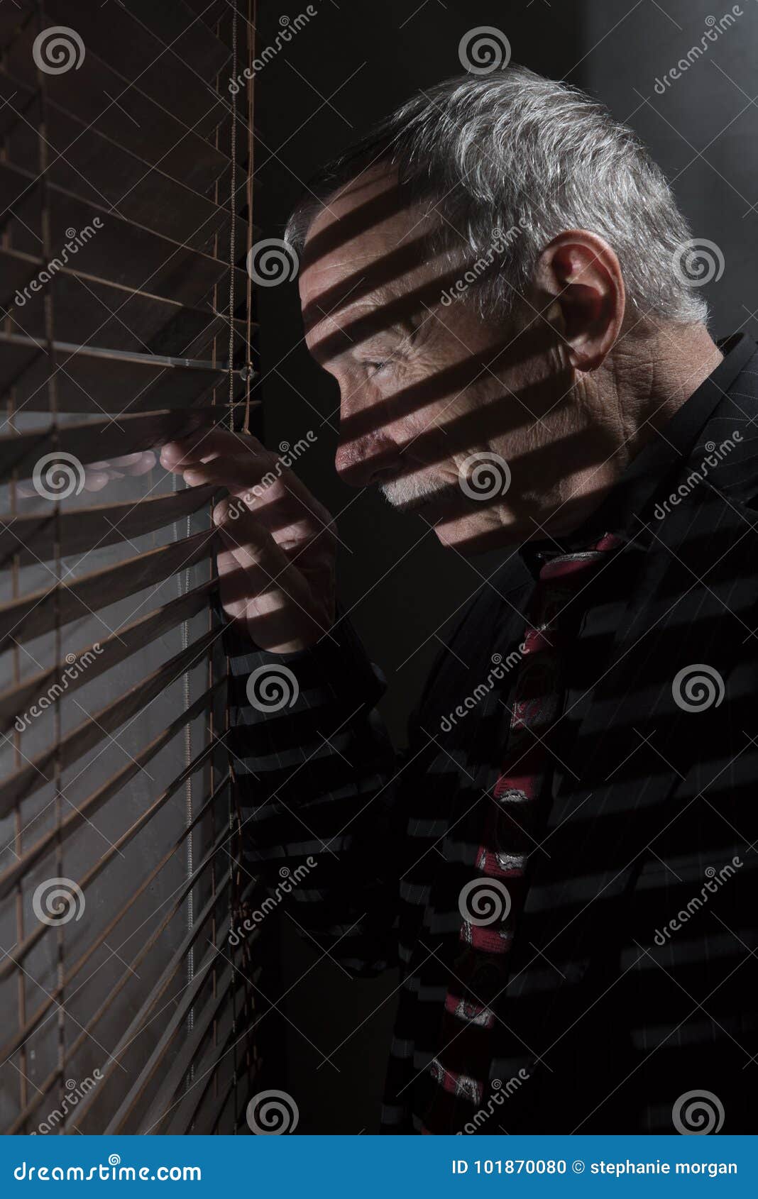 Mature Man Looking Out of a Window with Blinds Casting Shadows Stock ...