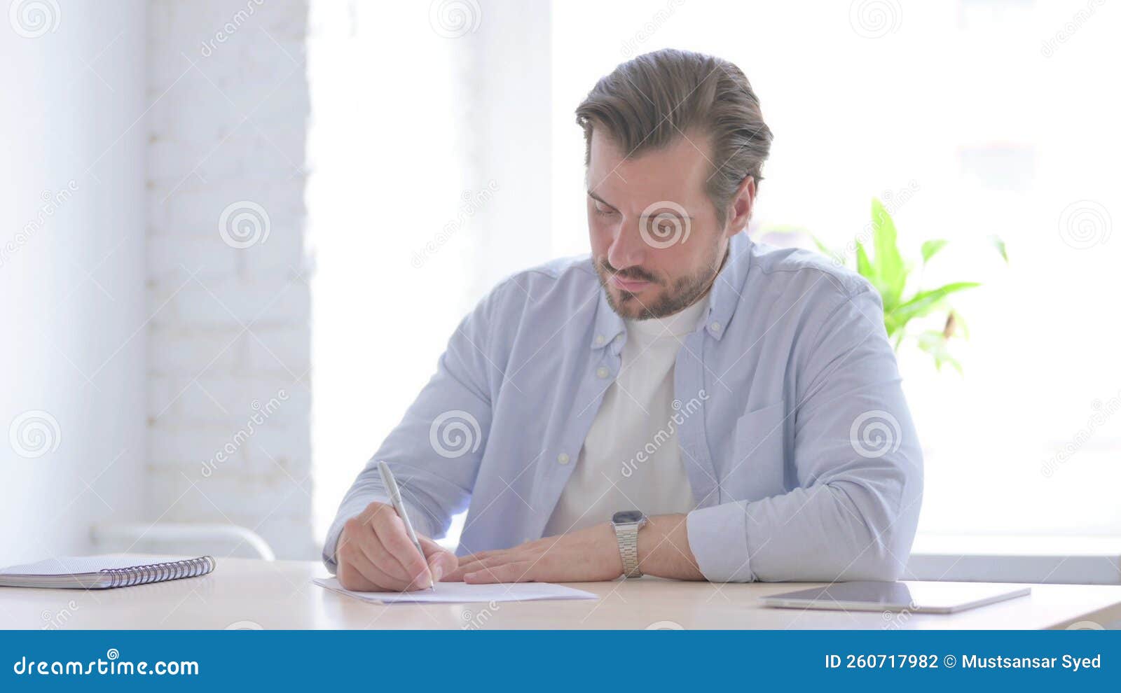 Young Man Writing on Paper in Office Stock Photo - Image of office ...