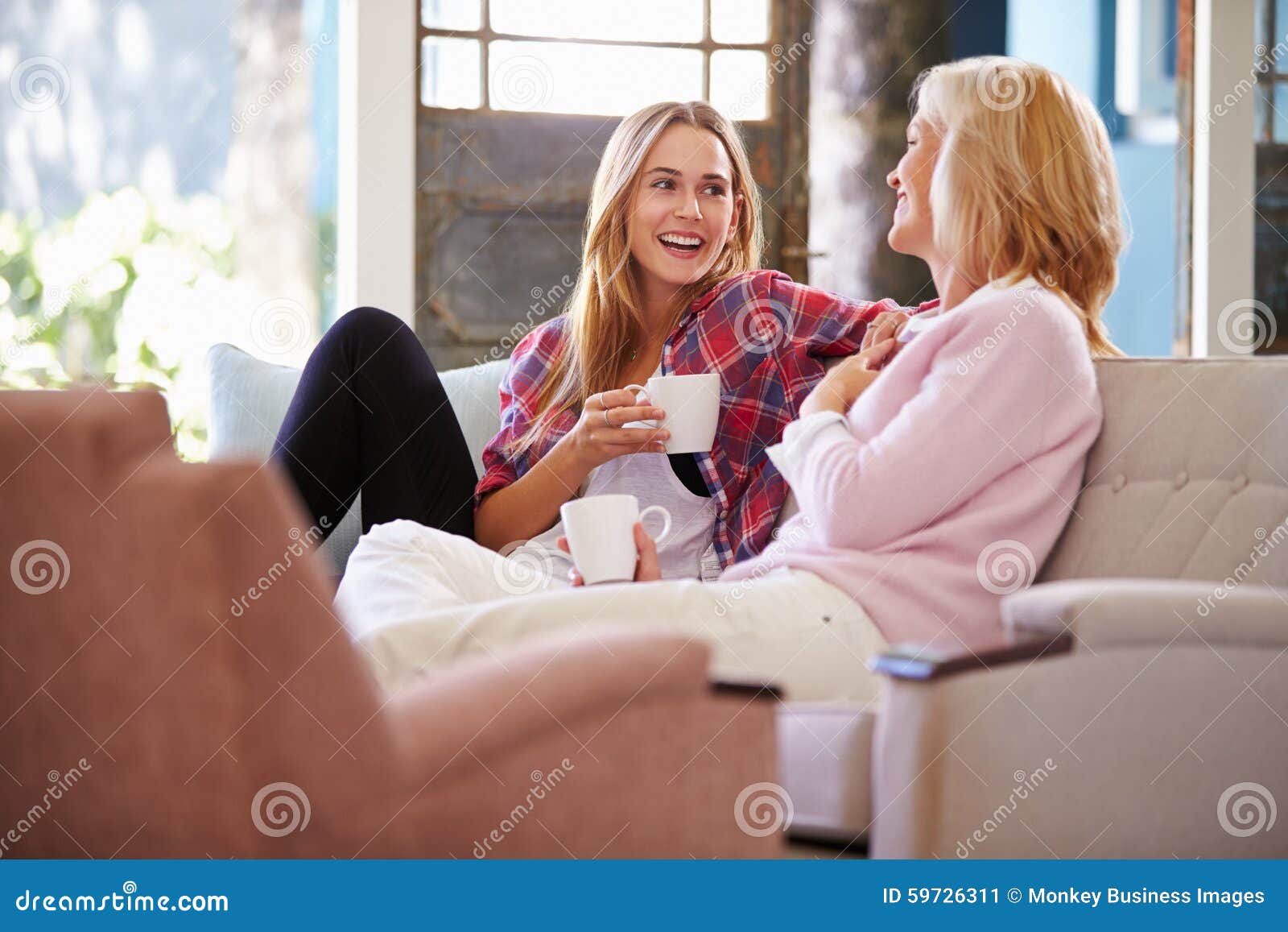 Mature Mother With Adult Daughter Relaxing On Sofa At Home Stock Image