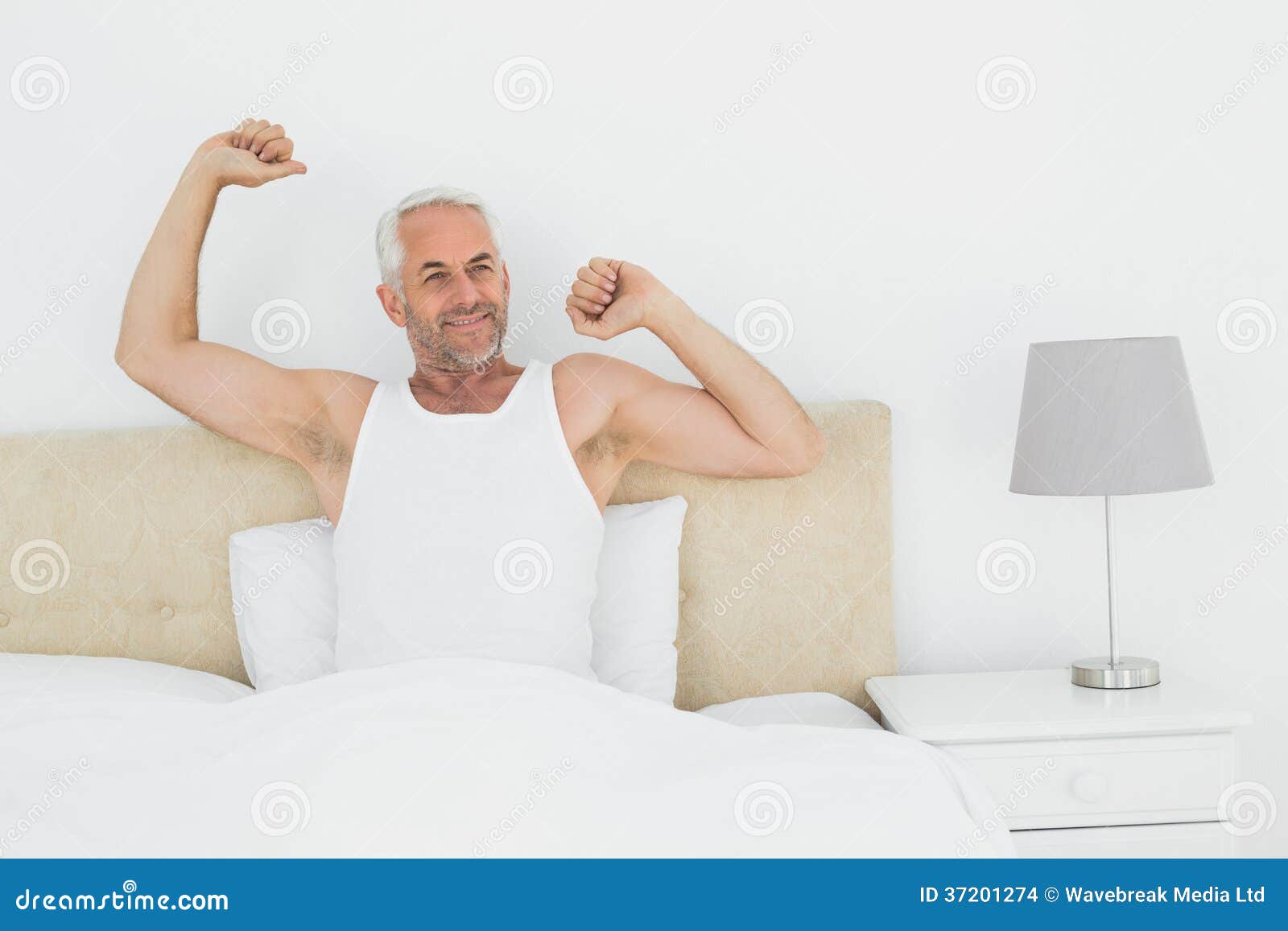 Mature Smiling Man Stretching Arms in Bed Stock Photo - Image of awake ...