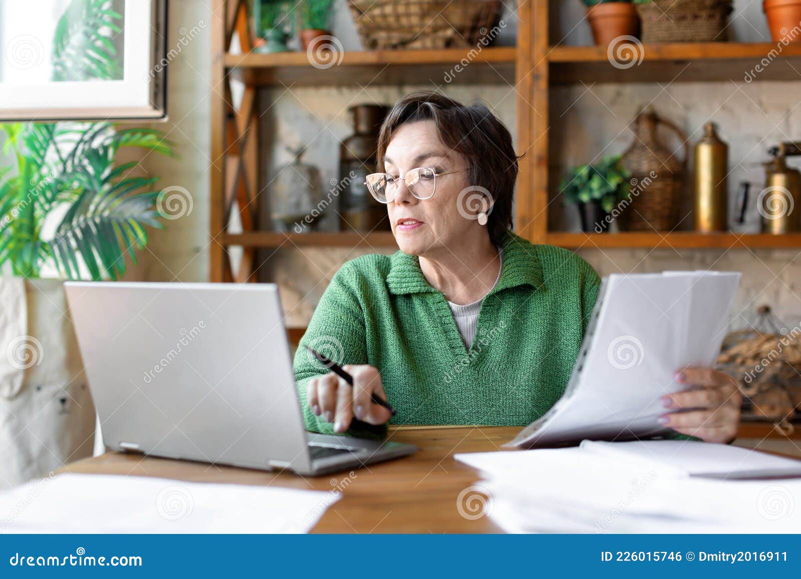 Mature Woman while Filling Out Documents. she Uses an Online Tutorial ...