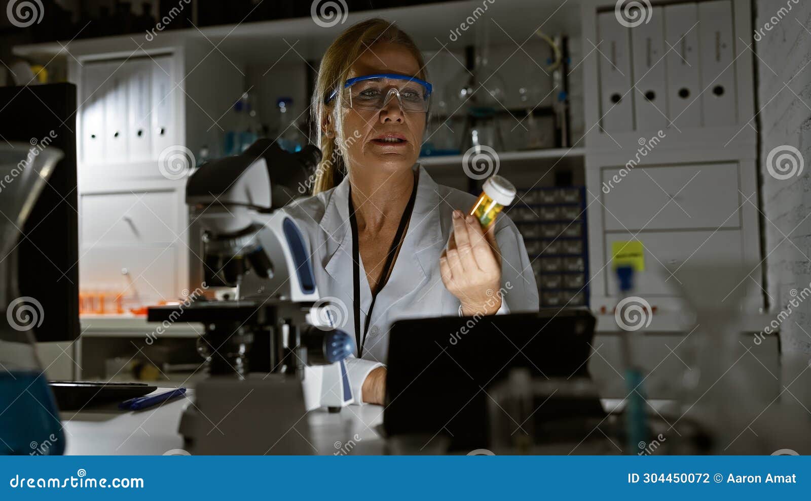 Mature Woman Scientist Analyzing Medication in a Laboratory Setting with Microscope and Computer ...
