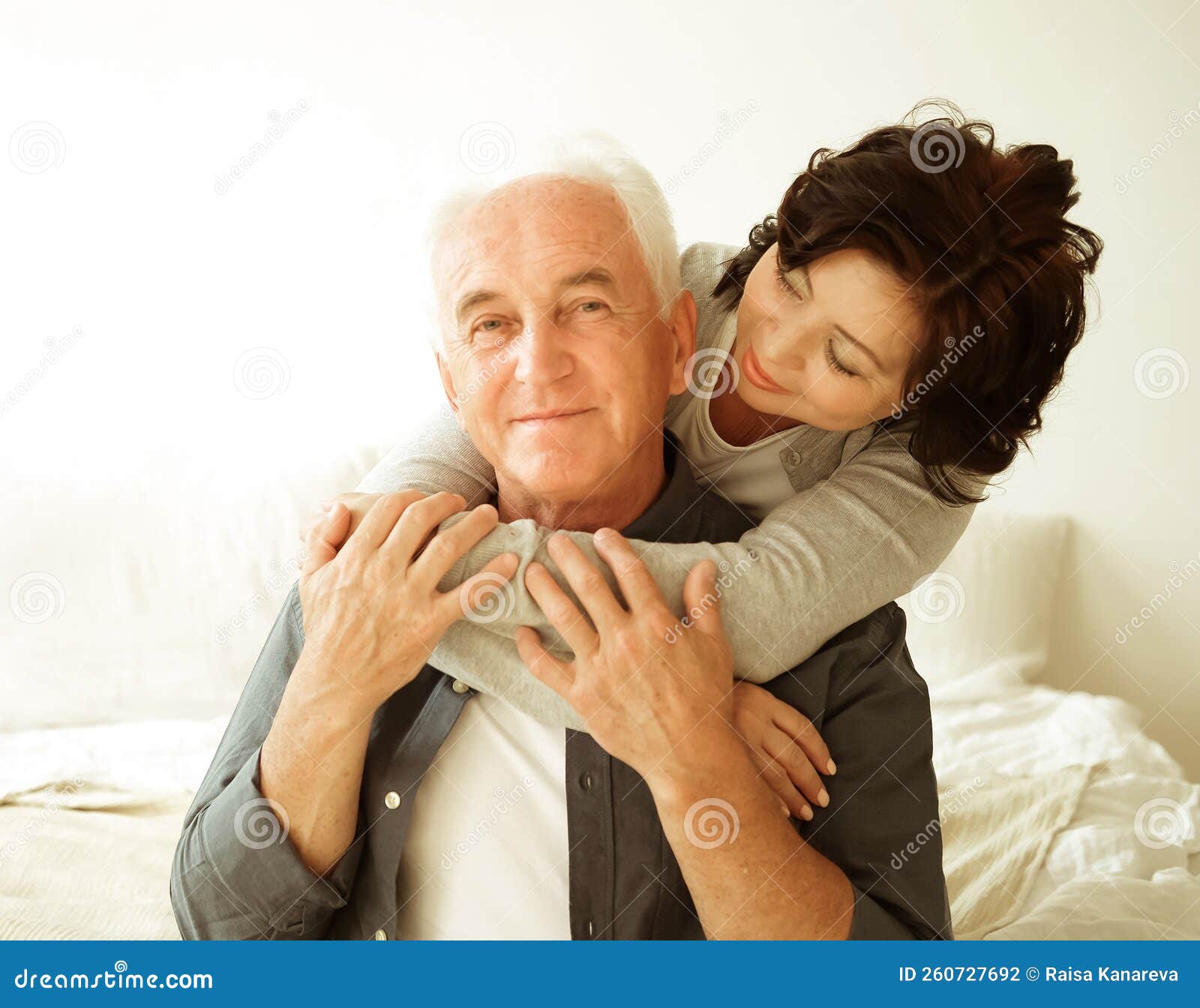 Mature 60 Year Old Couple Hugging while Sitting on the Bed in the ... Mature 60 Year Old Couple Hugging while Sitting on the Bed in the ...