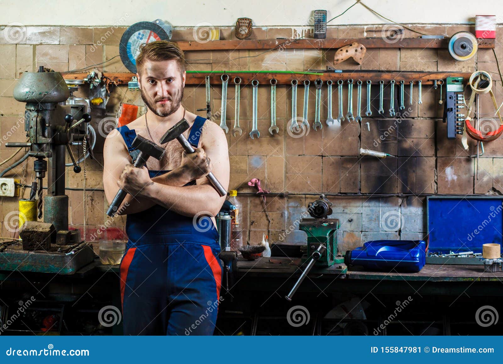 Mechanic in a Car Garage Stands at the Desktop with Hammers in His ...
