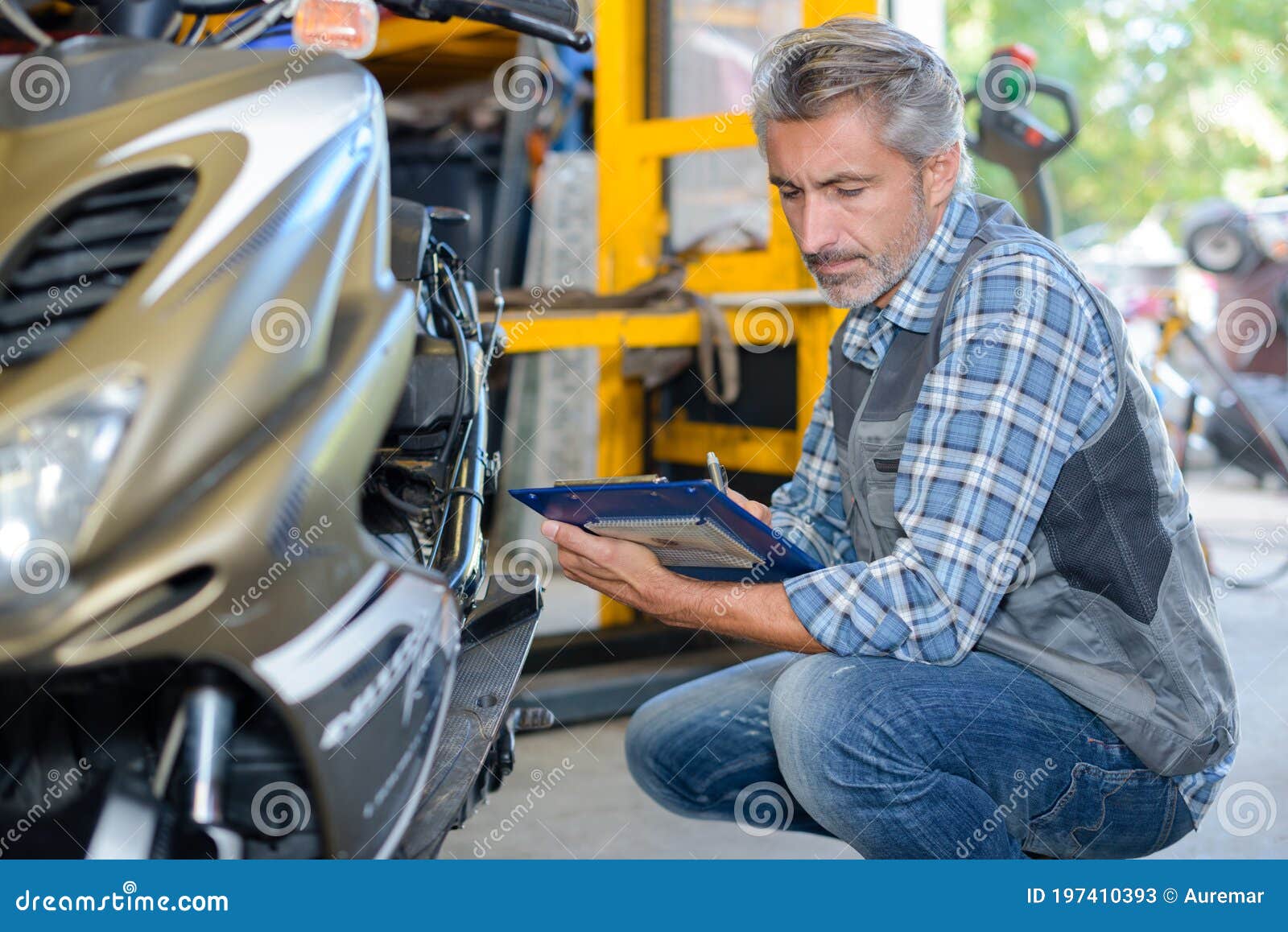 Mechanic Crouched beside Scooter Holding Clipboard Stock Image - Image ...