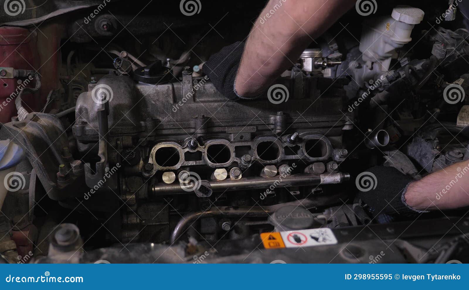 A Mechanic Disassembling the Engine Under the Hood of a Car at a ...