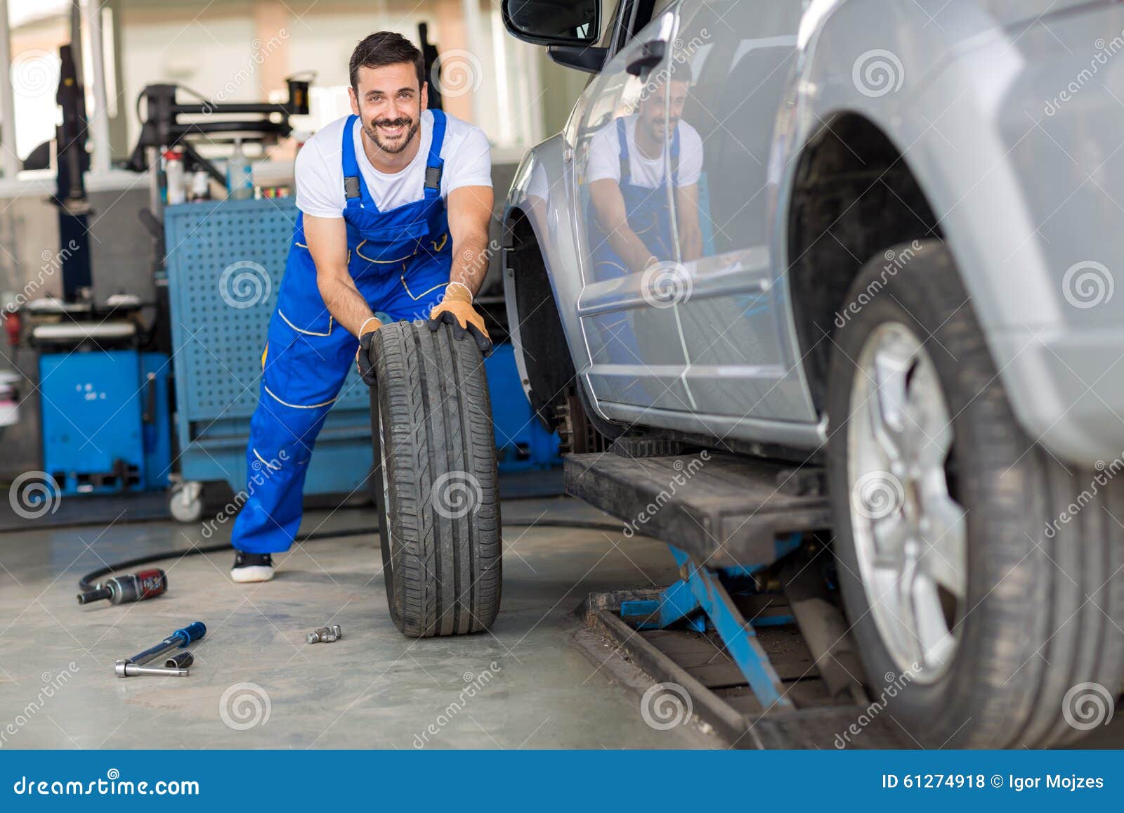 Mechanic Hands in Blue Uniform Pushing a Black Tyre Stock Photo - Image ...
