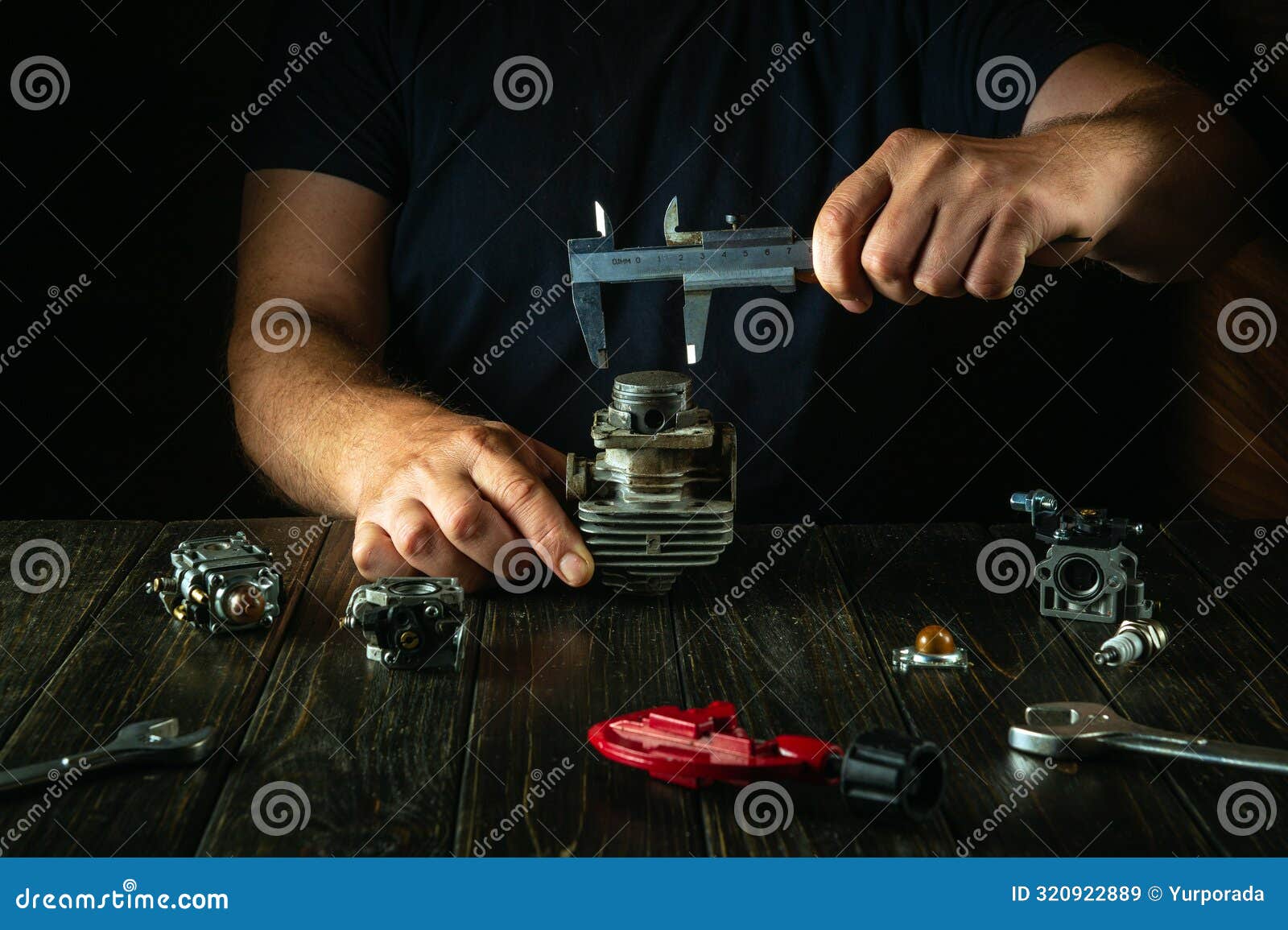 The Mechanic at His Desk in the Workshop Repairs the Engine of a Lawn Mower after a Breakdown ...