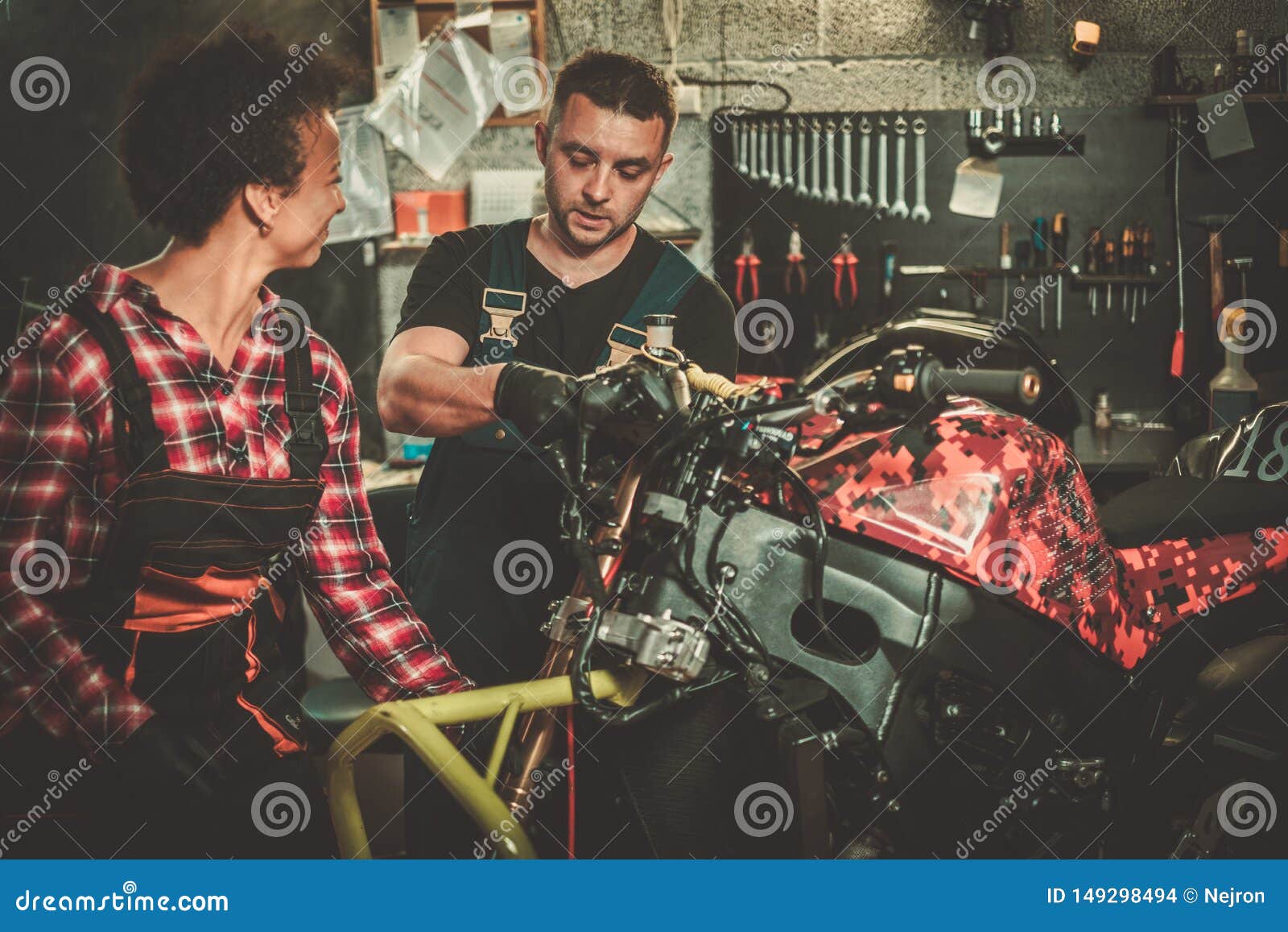 Mechanic and His Helper Repairing a Motorcycle in a Workshop Stock ...