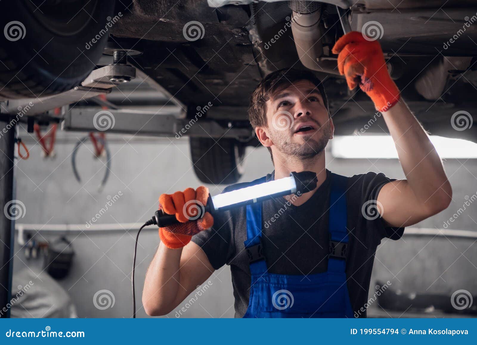 A Mechanic Lights Up the Car Bottom with a Flashlight Stock Photo ...