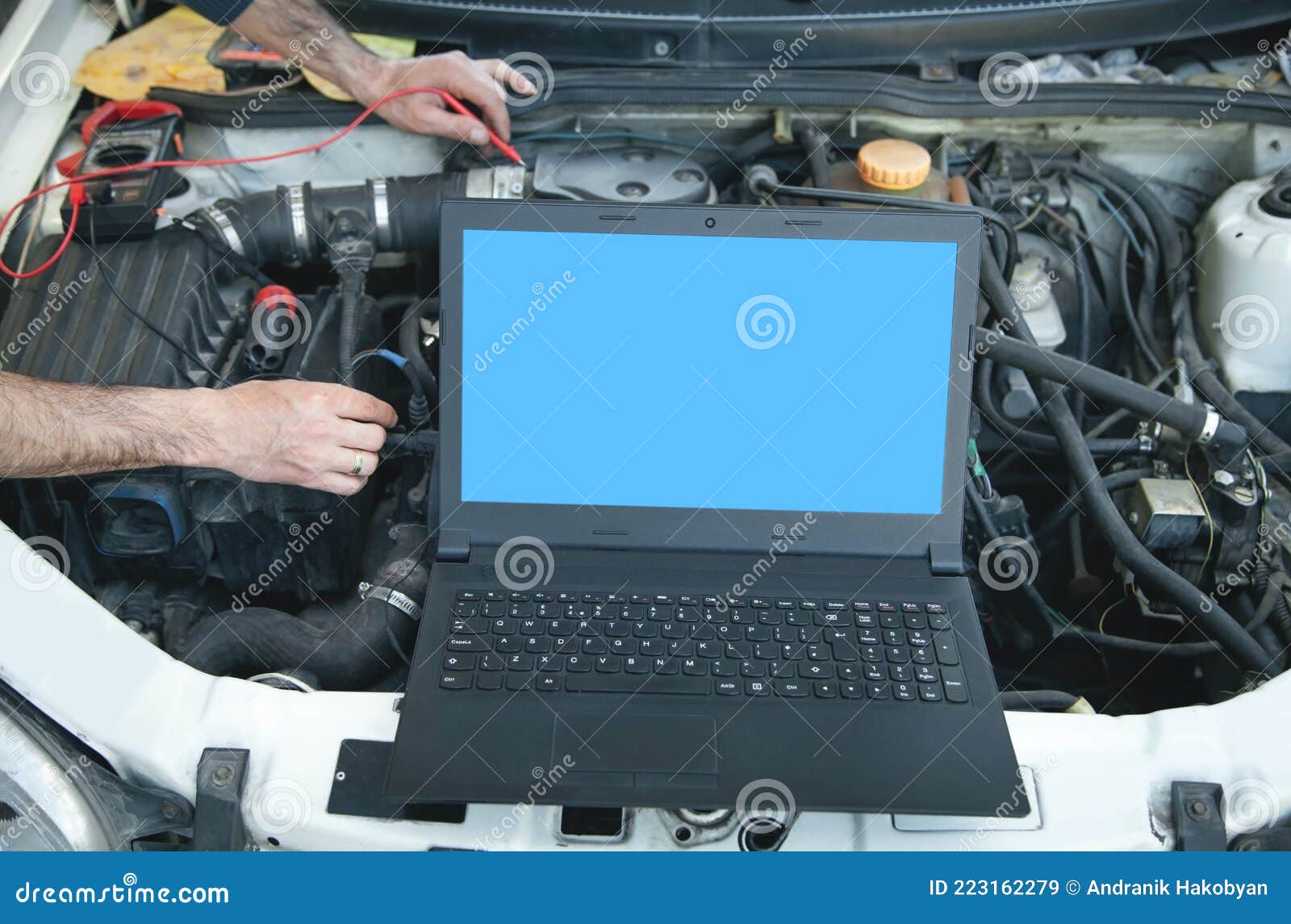 Mechanic with a Multimeter Testing Car Engine. Laptop on Car Engine ...