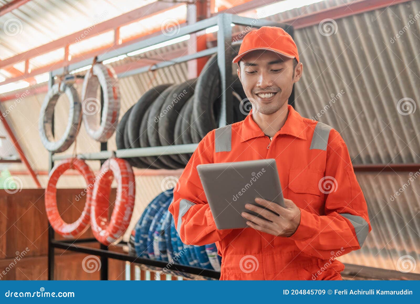 Mechanic in Red Wearpack and Hat Using a Pad Stock Image - Image of ...