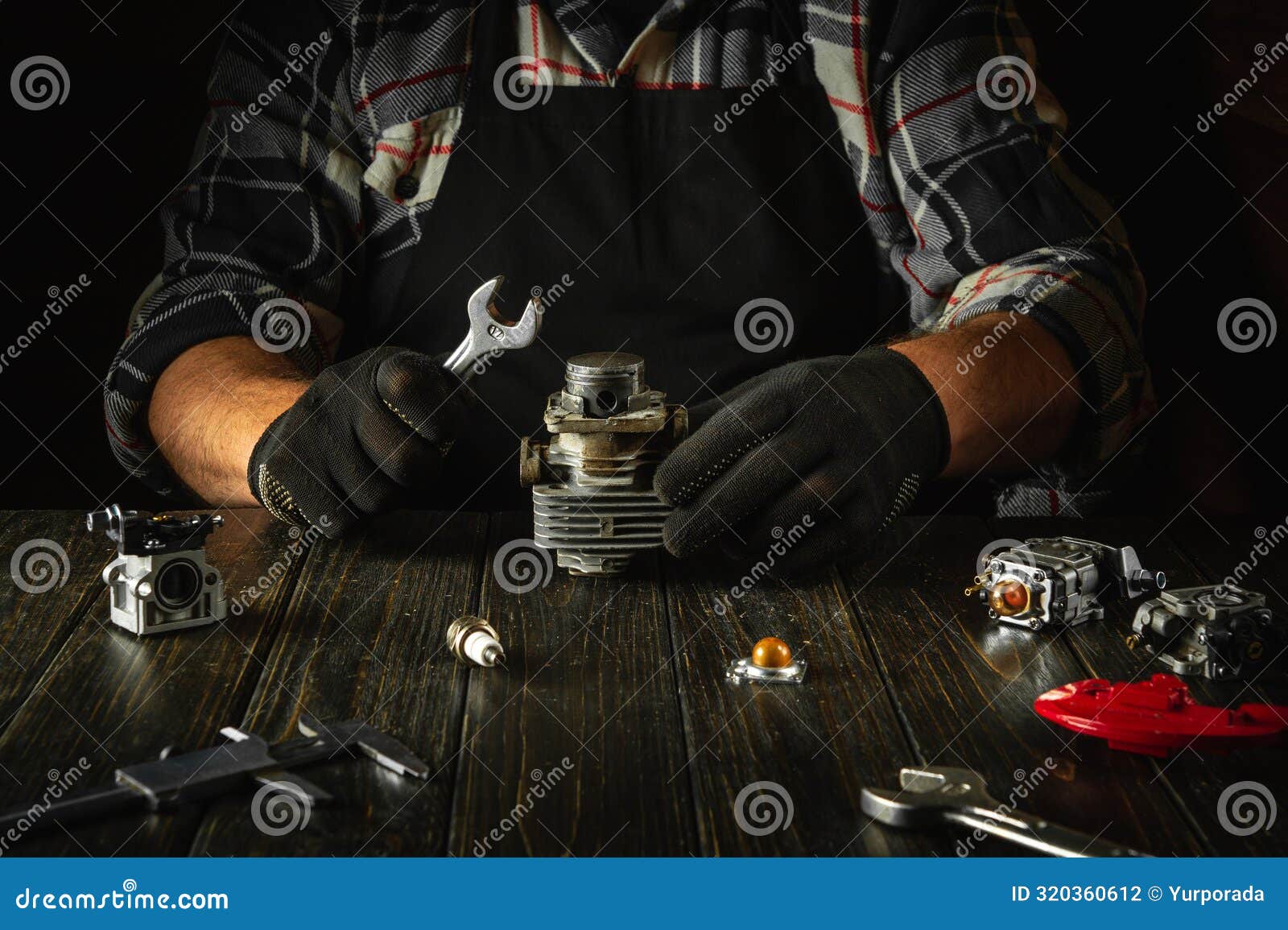 A Mechanic at a Workbench in a Workshop Repairs an Old Chainsaw Engine ...